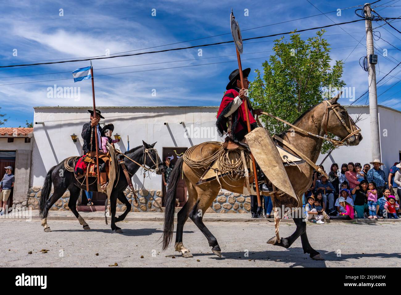 A young gaucho in traditional dress rides with his father in a parade ...