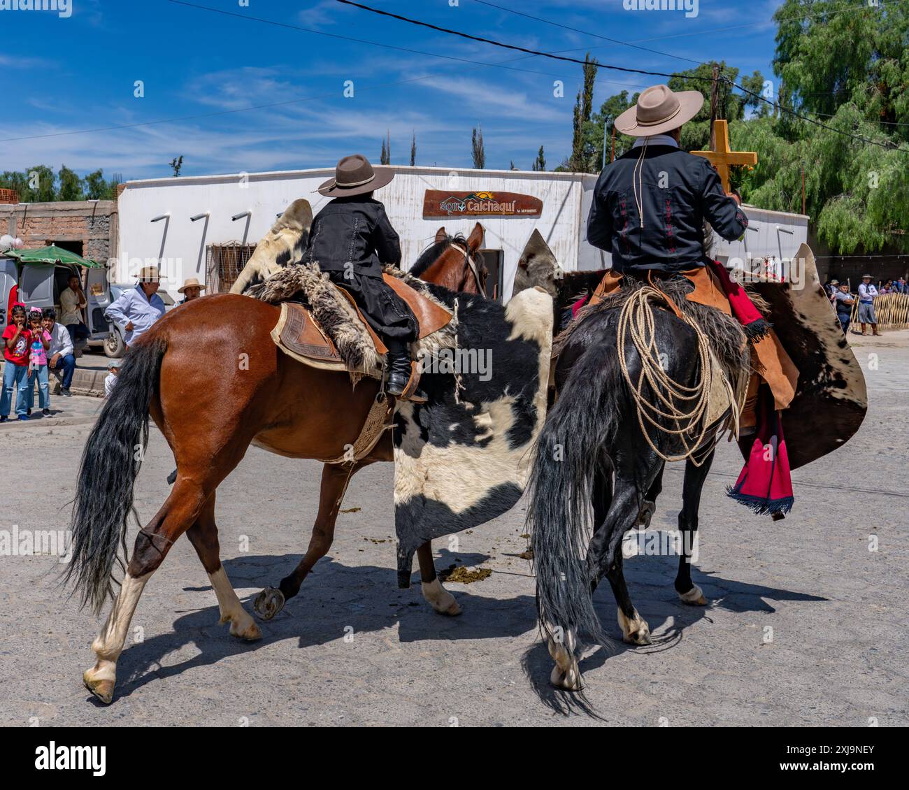 A young gaucho in traditional dress rides with his grandfather in a ...