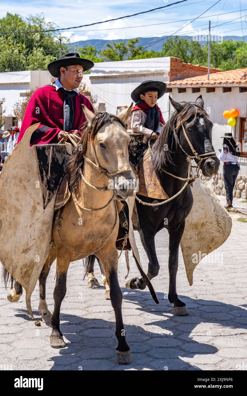 A young gaucho in traditional dress rides with his father in a parade ...