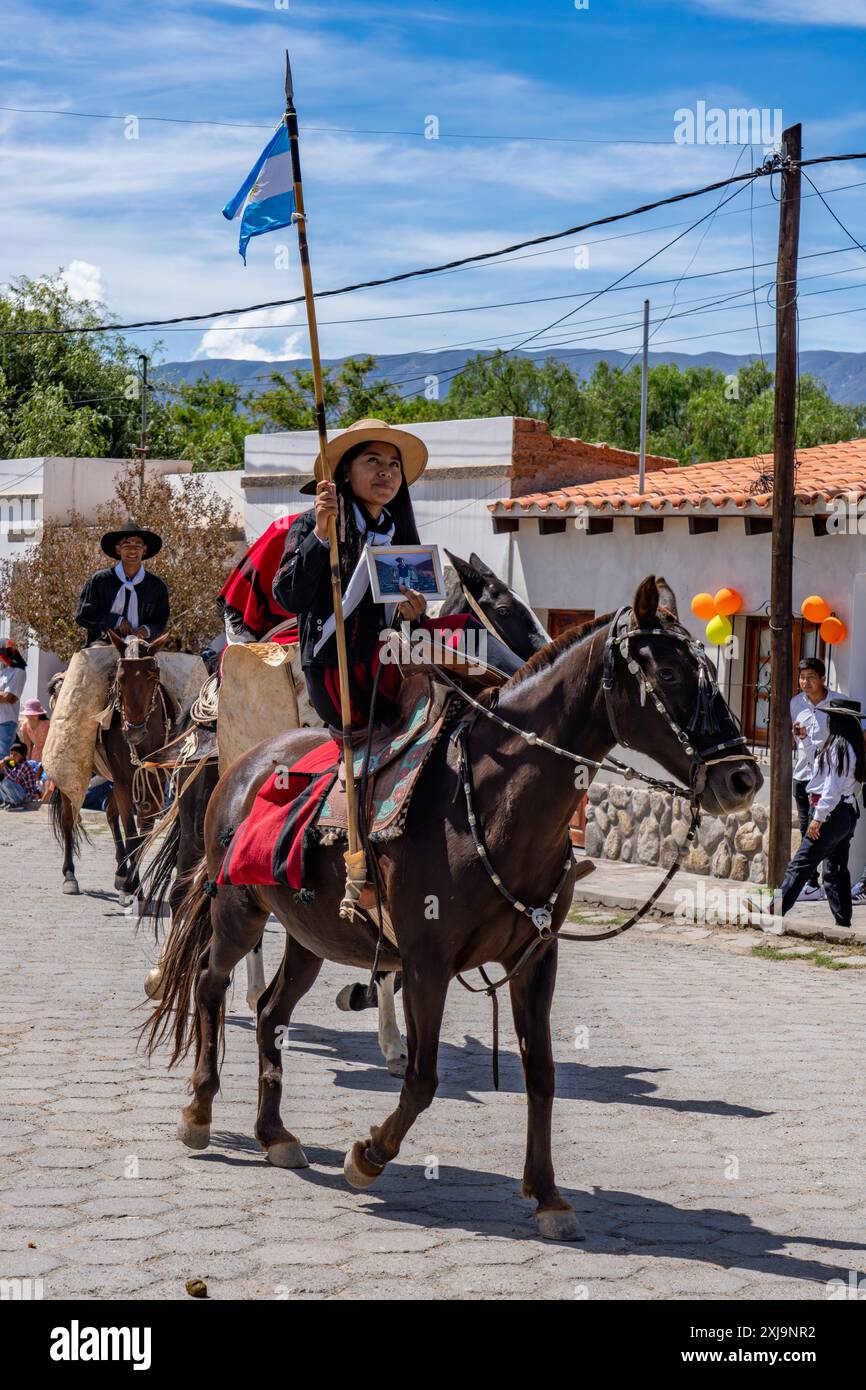 A female gaucho wearing a traditional red Salteño poncho rides ...