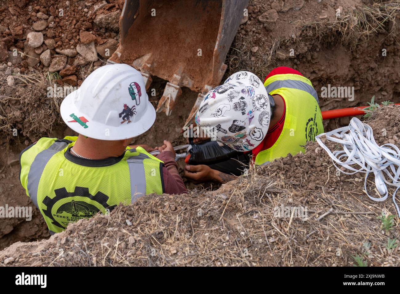 Workers installing plastic conduit for internet fiber optic cable ...