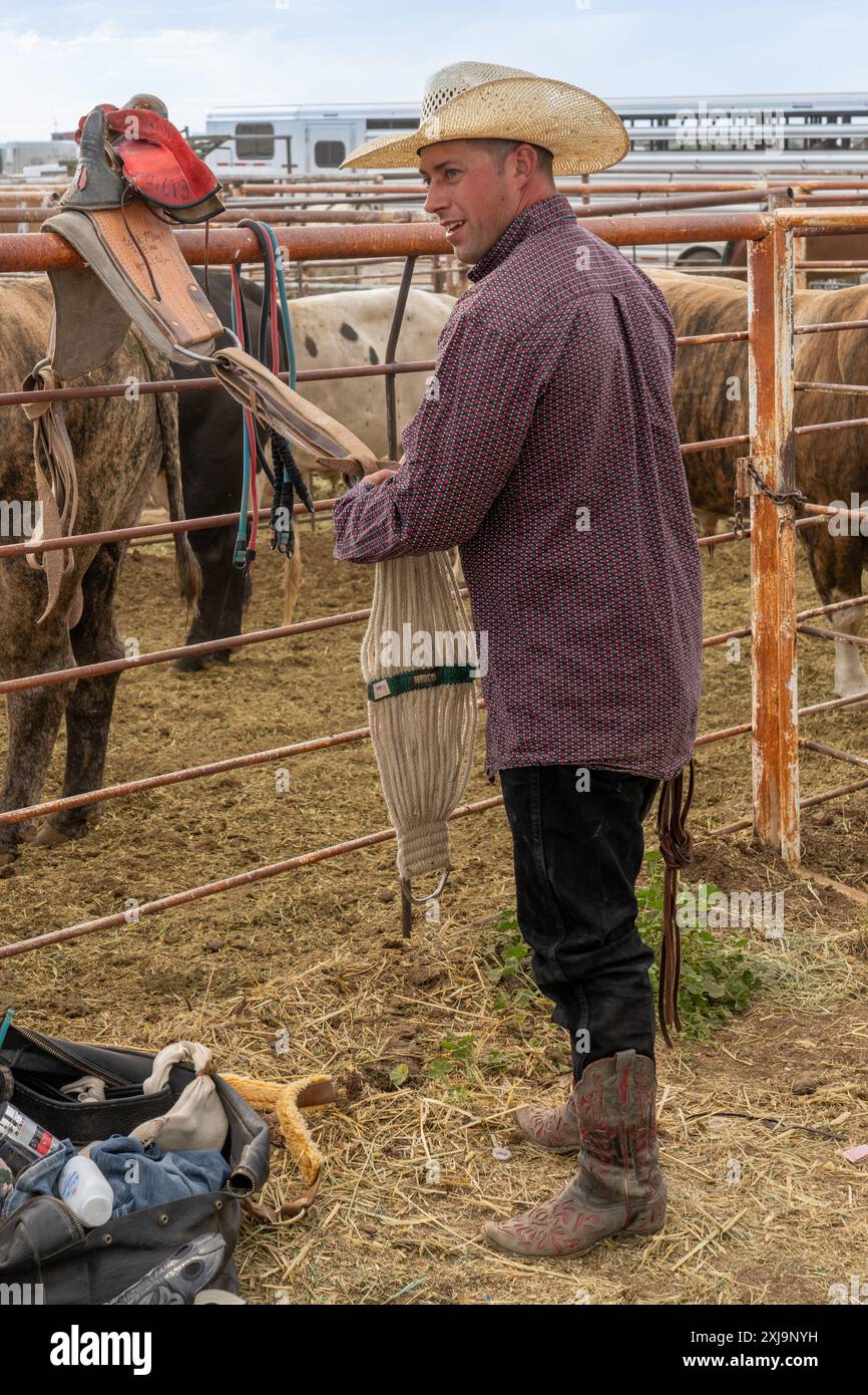 A rodeo cowboy adjusts his bareback rigging before his bareback bronc ...