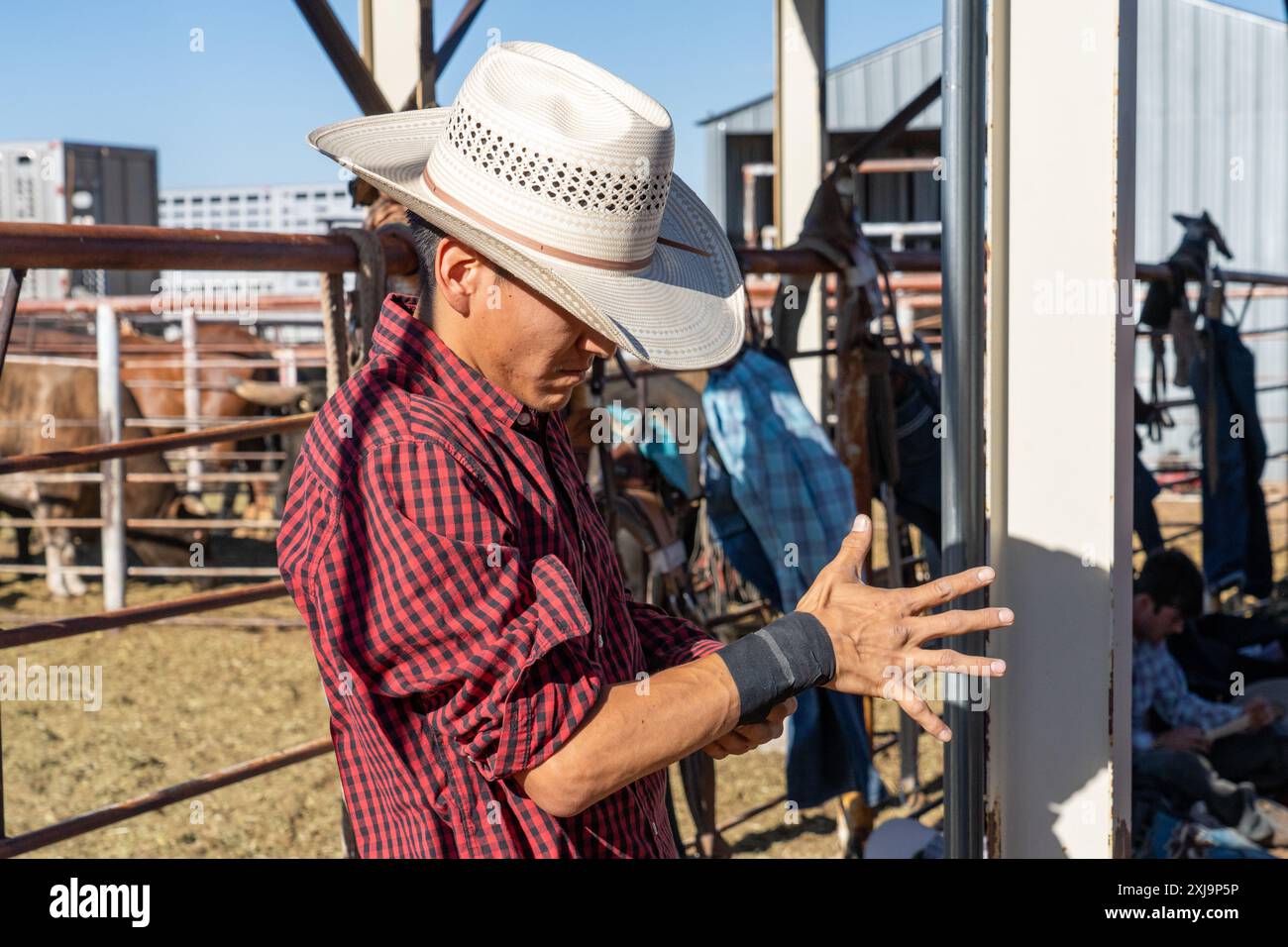 A Navajo rodeo cowboy wraps his wrist with athletic tape before his ...