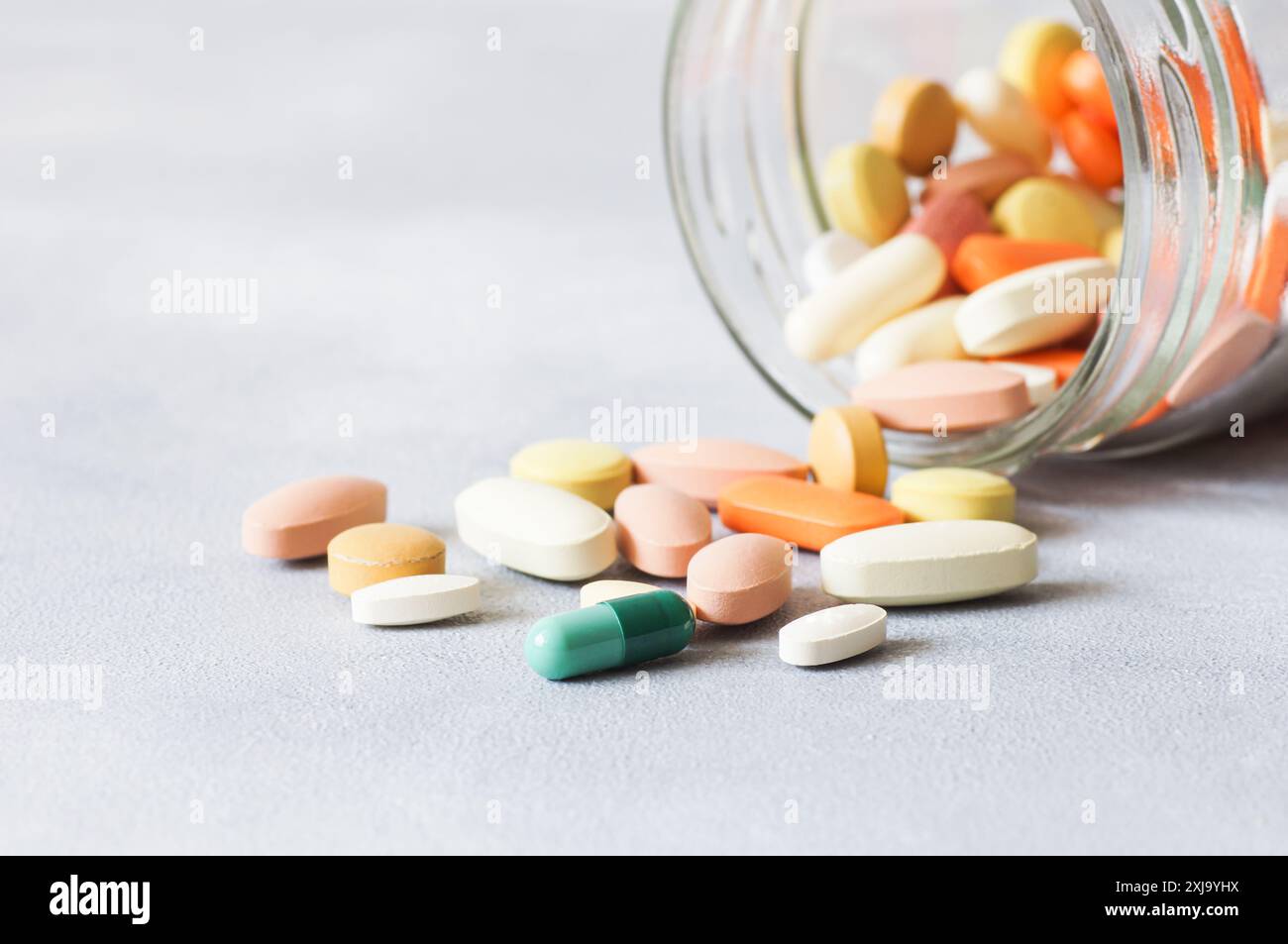Colorful tablet, capsules, pills medicine spilling out of glass bottle ...