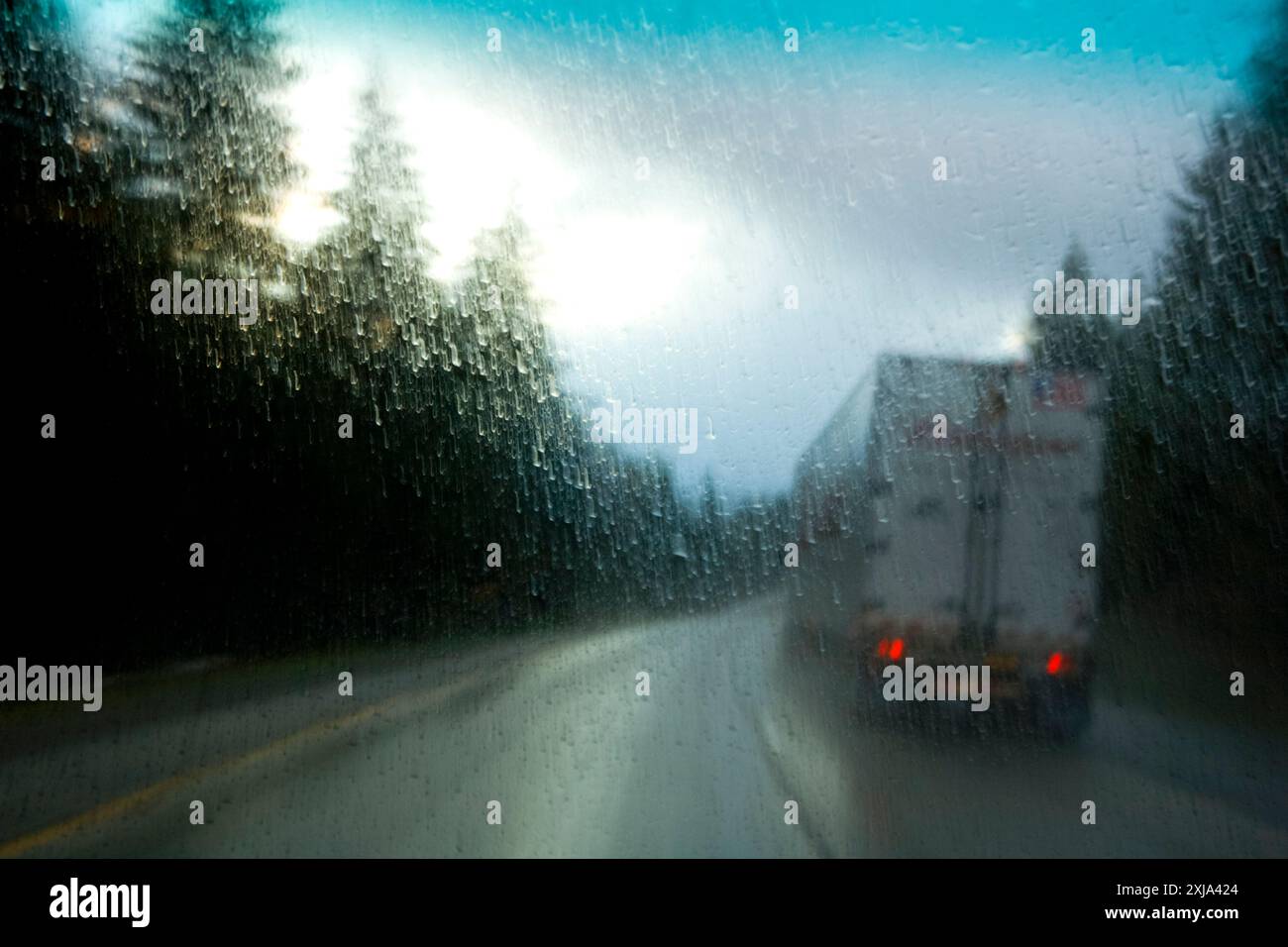 Semi-truck driving in heavy rain on an interstate highway through trees ...