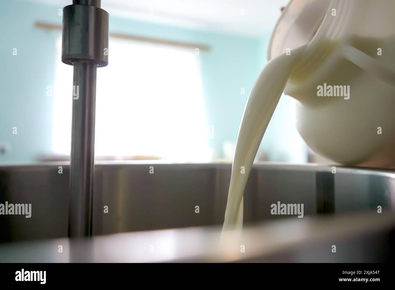 A close-up of fresh milk being transferred from a container to a ...