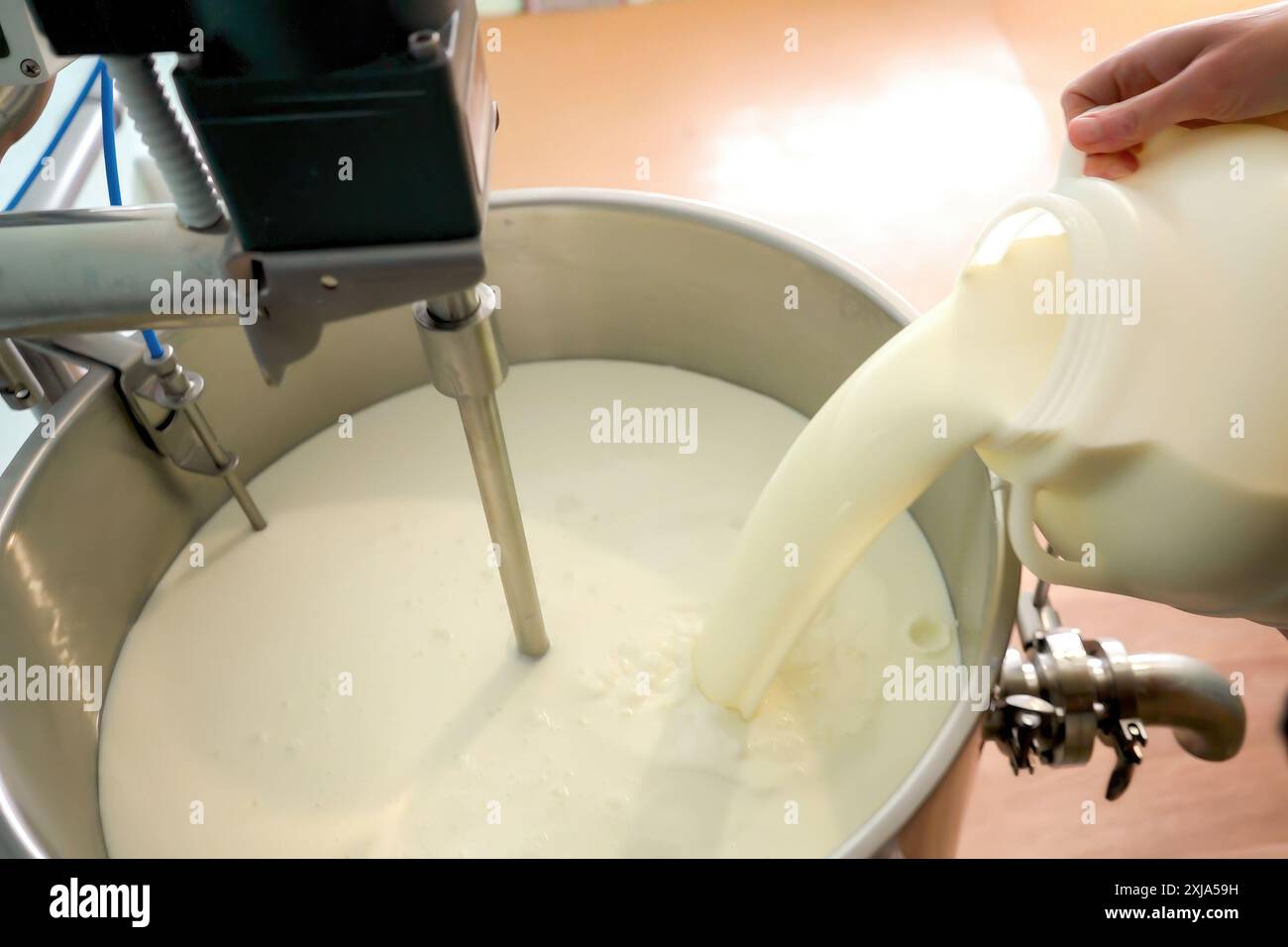 A close-up of fresh milk being transferred from a container to a ...