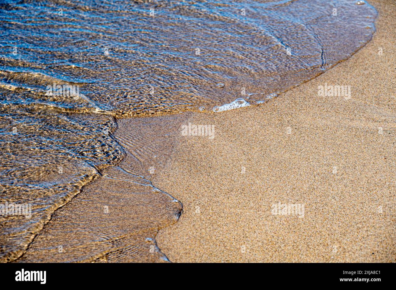 Water ebbing and flowing on sandy beach Stock Photo - Alamy