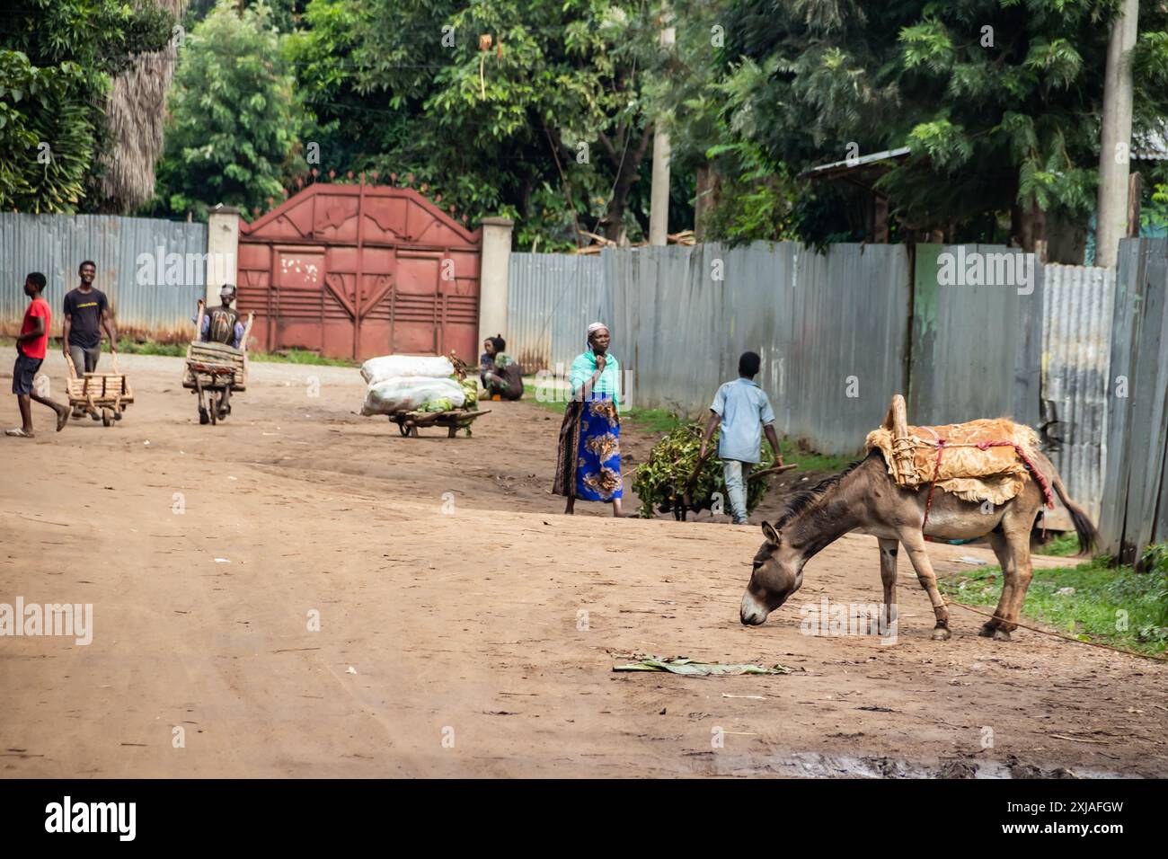 Dusty and Colorful African Village Street Scene with People passing and ...