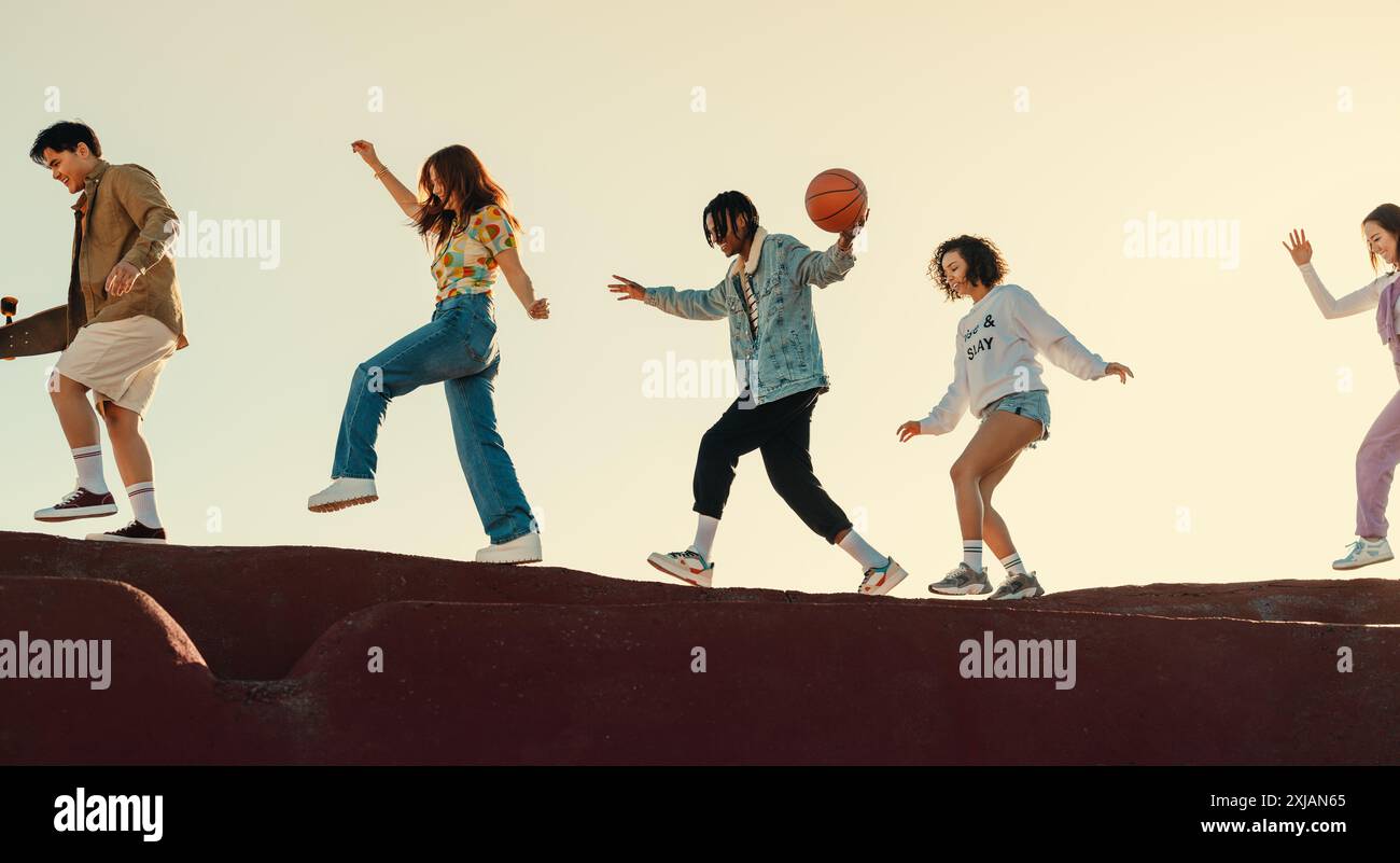 A group of young people walking side by side on a ledge, having fun and ...