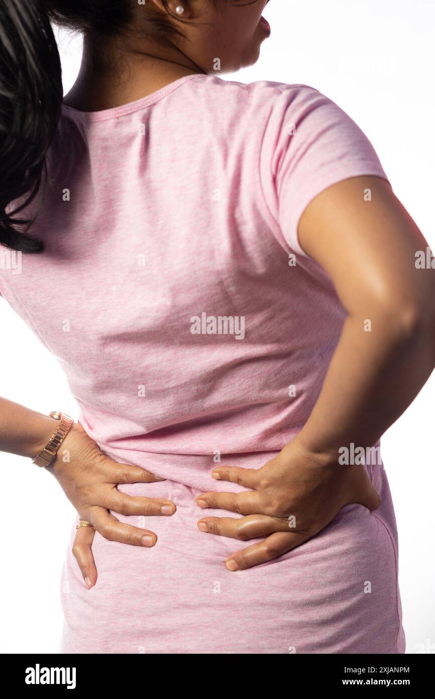 An Indian unrecognizable woman holding her back for pain showing ...