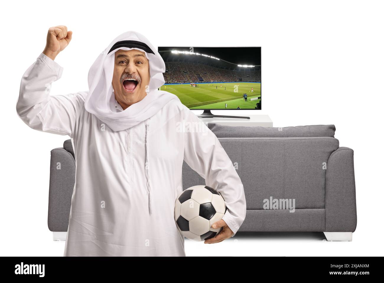 Happy arab man with a football cheering in front of tv and sofa ...
