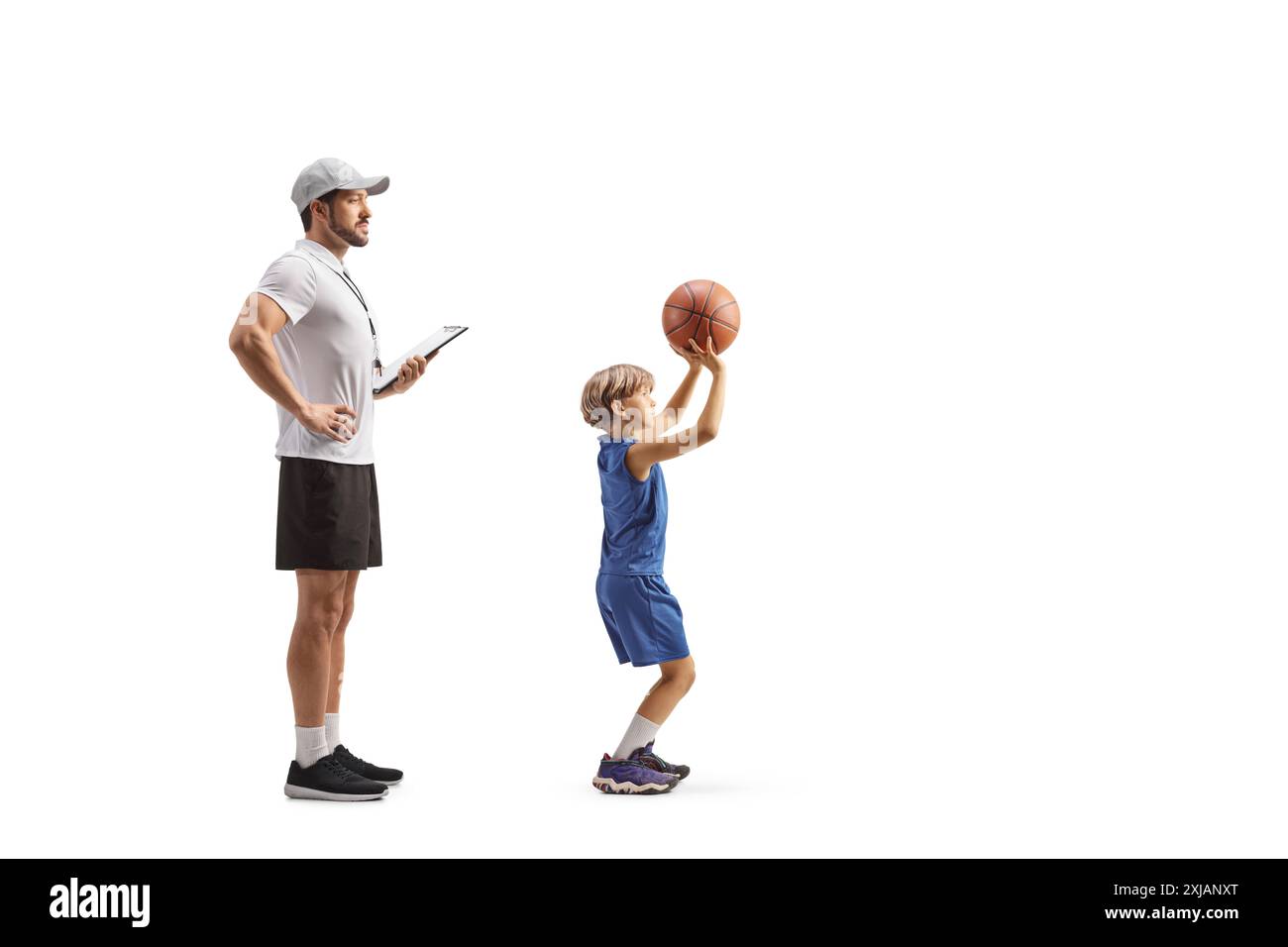 Full length profile shot of coach watching a boy shooting a basketball ...