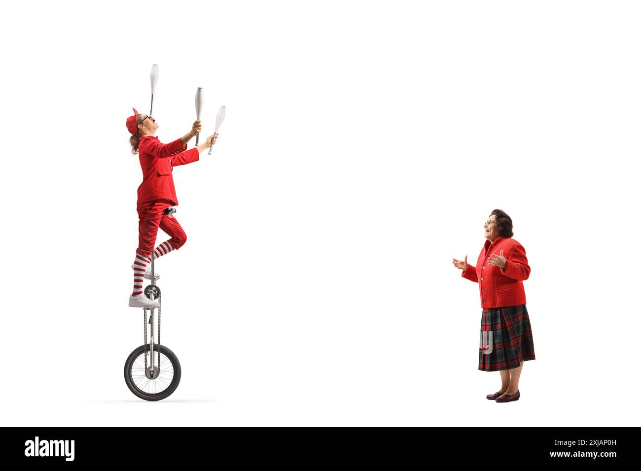 Amused elderly woman watching an acrobat riding a giraffe unicycle and ...