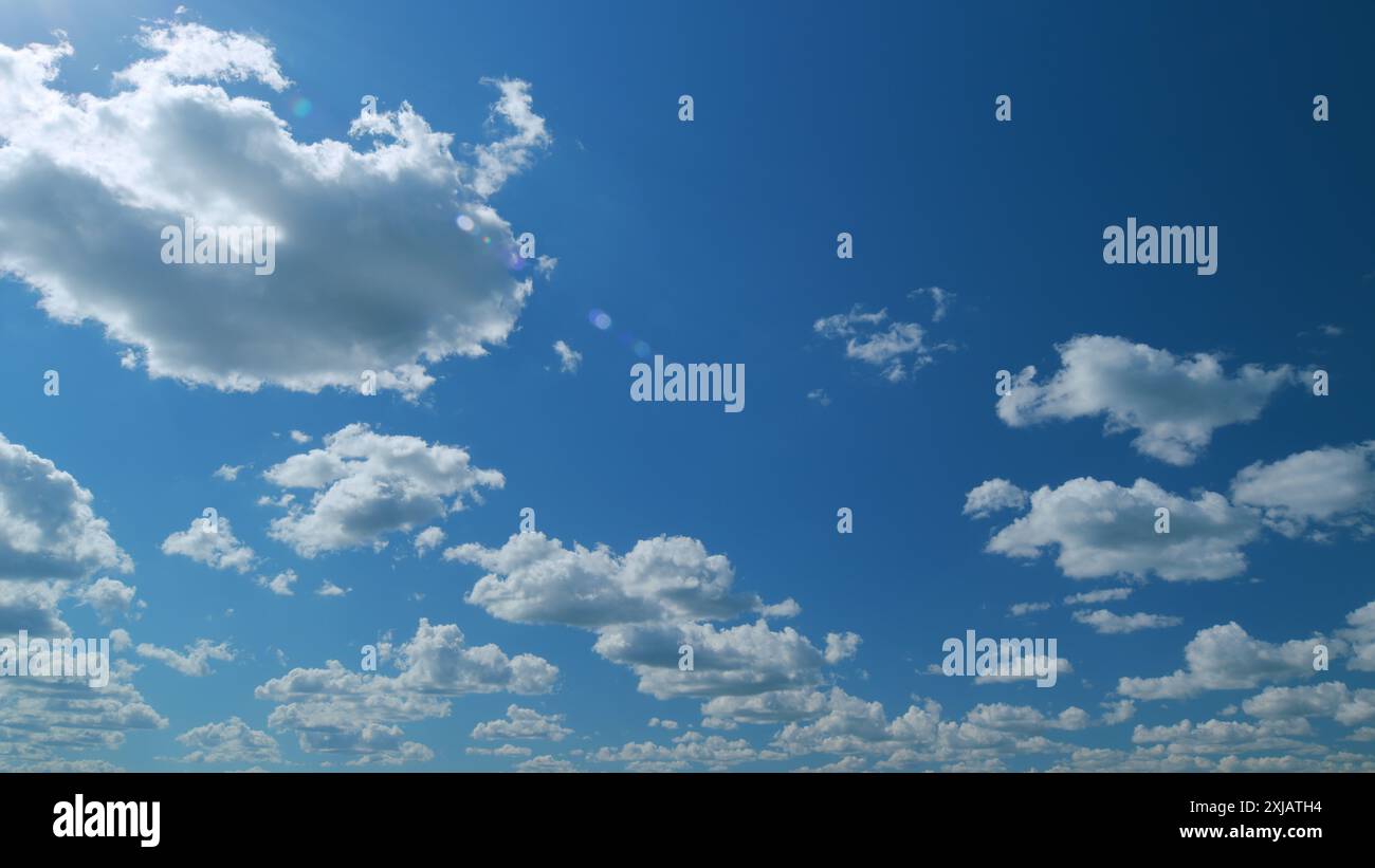 Time lapse. Clouds running across the blue sky. White puffy and fluffy ...