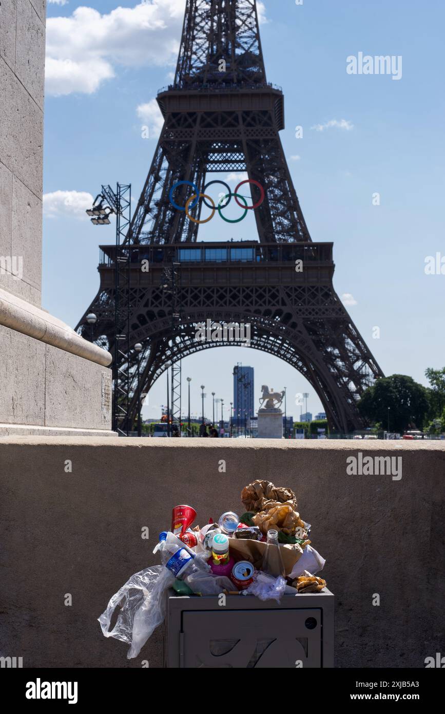 An overflowing rubbish bin on a pavement in front of the Eiffel Tower ...