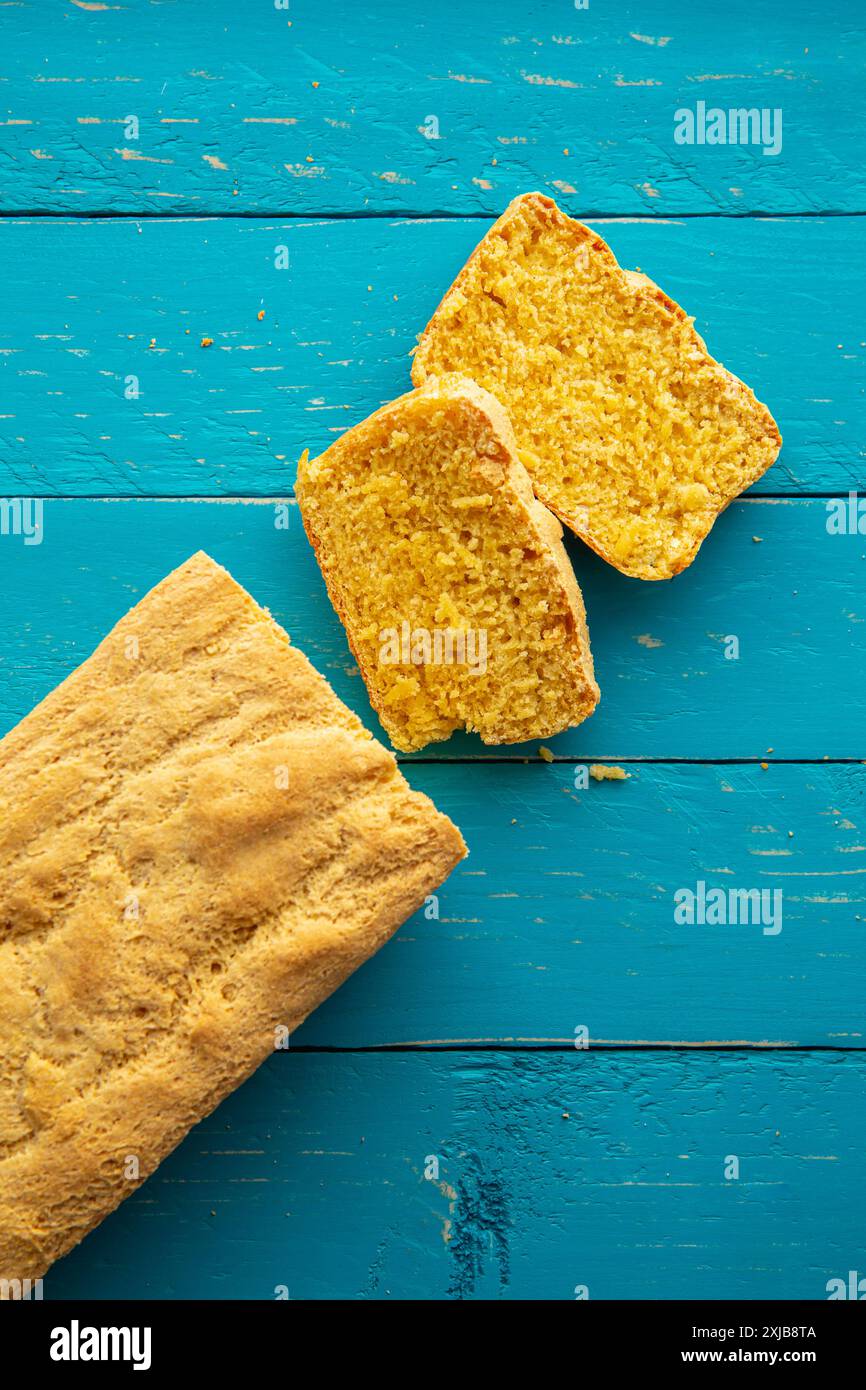 Beautiful homemade yellow sliced cornbread loaf on blue wood board ...