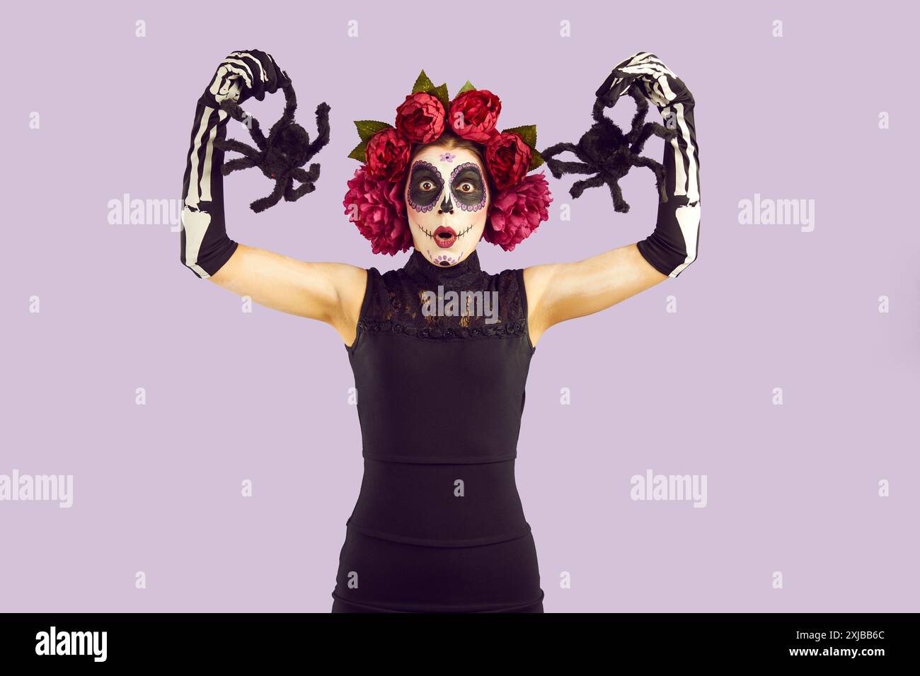 Woman in spooky Halloween costume holding toy spiders and making funny ...