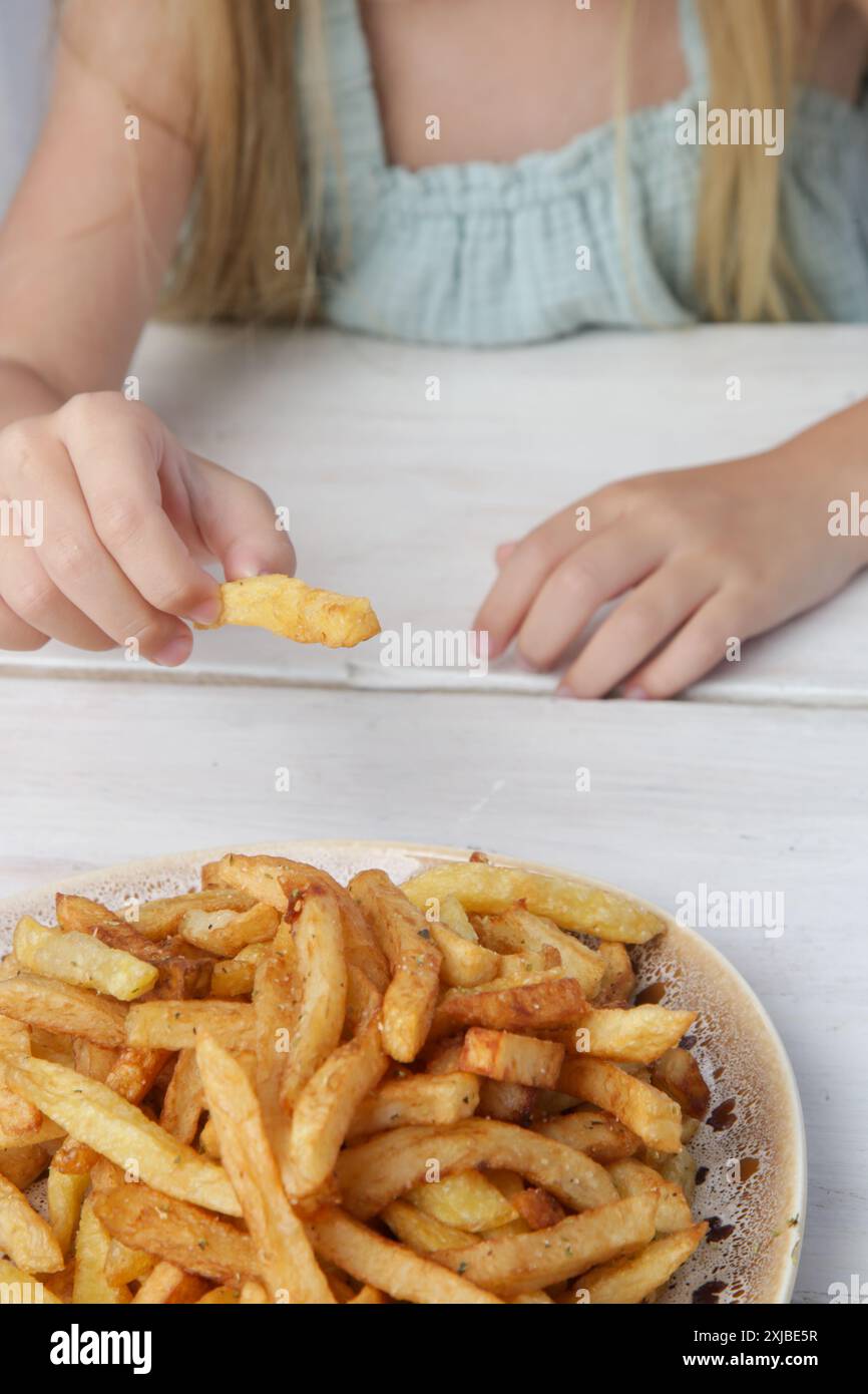 Little girl is eating french fries Stock Photo - Alamy