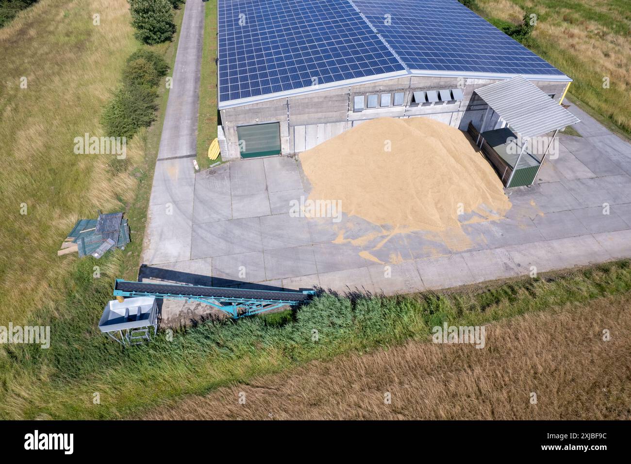 a mountain of grain lies in front of a silo Stock Photo - Alamy