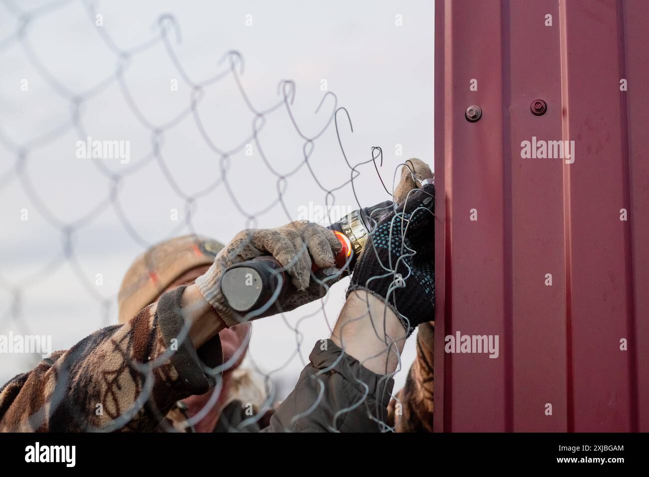 installation of galvanized metal mesh chain-link at the border of the ...