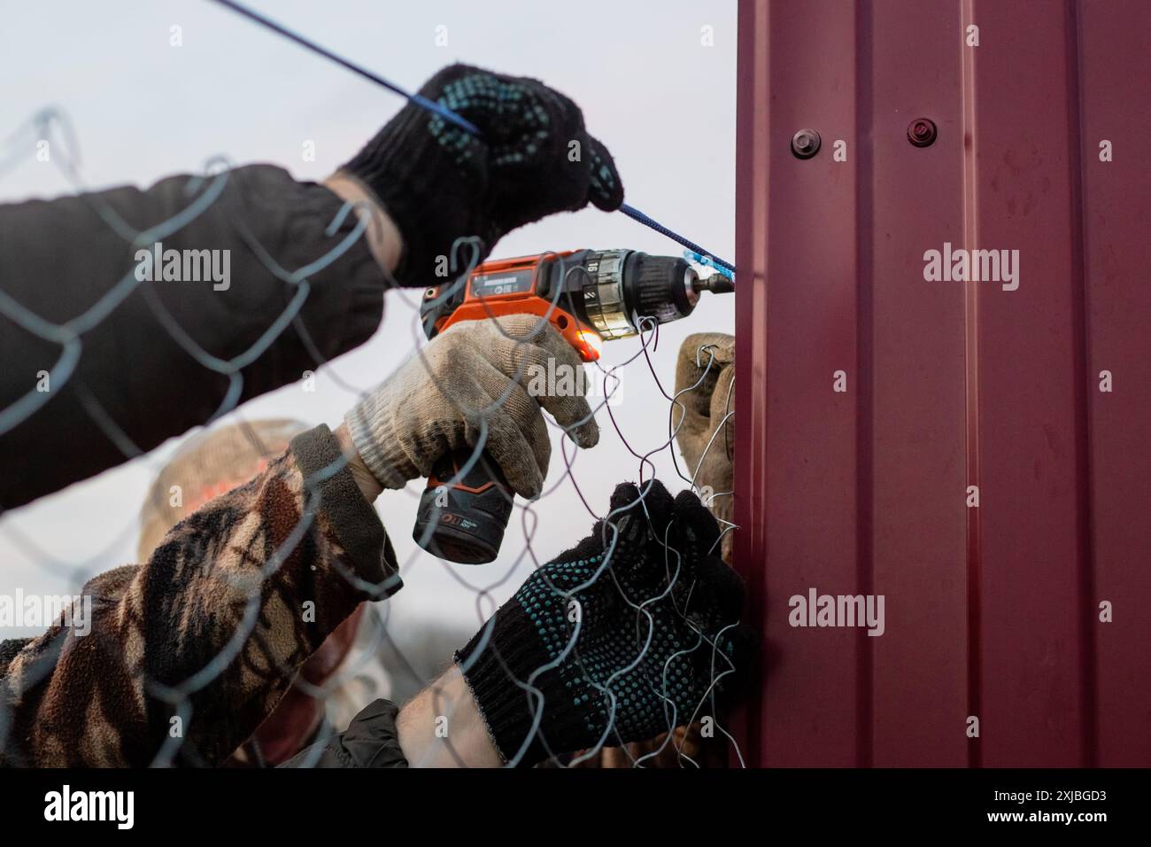 installation of galvanized metal mesh chain-link at the border of the ...