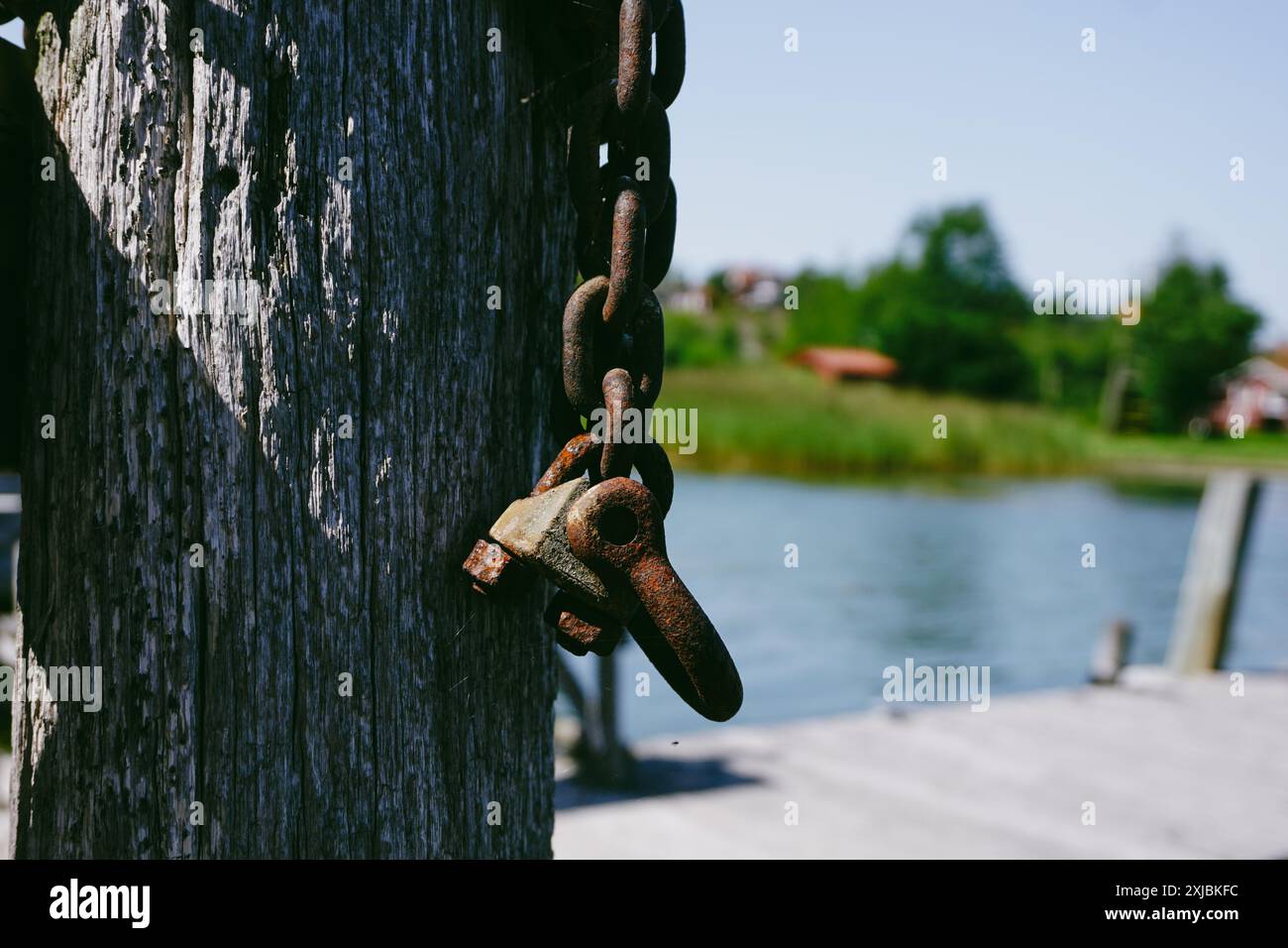 A chain hanging from a wooden post Stock Photo - Alamy