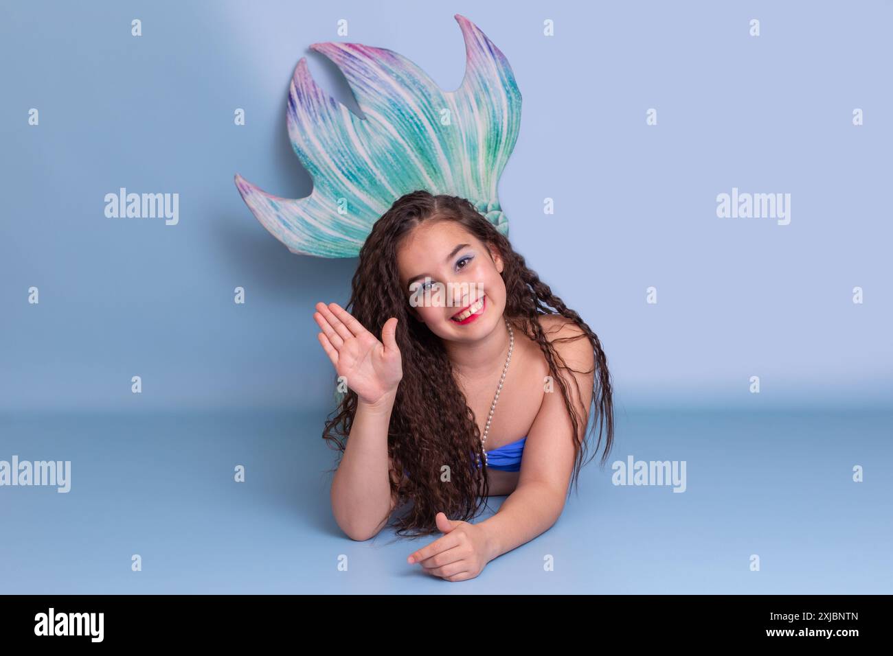 Beautiful girl in a mermaid costume, friendly, lies on a blue ...