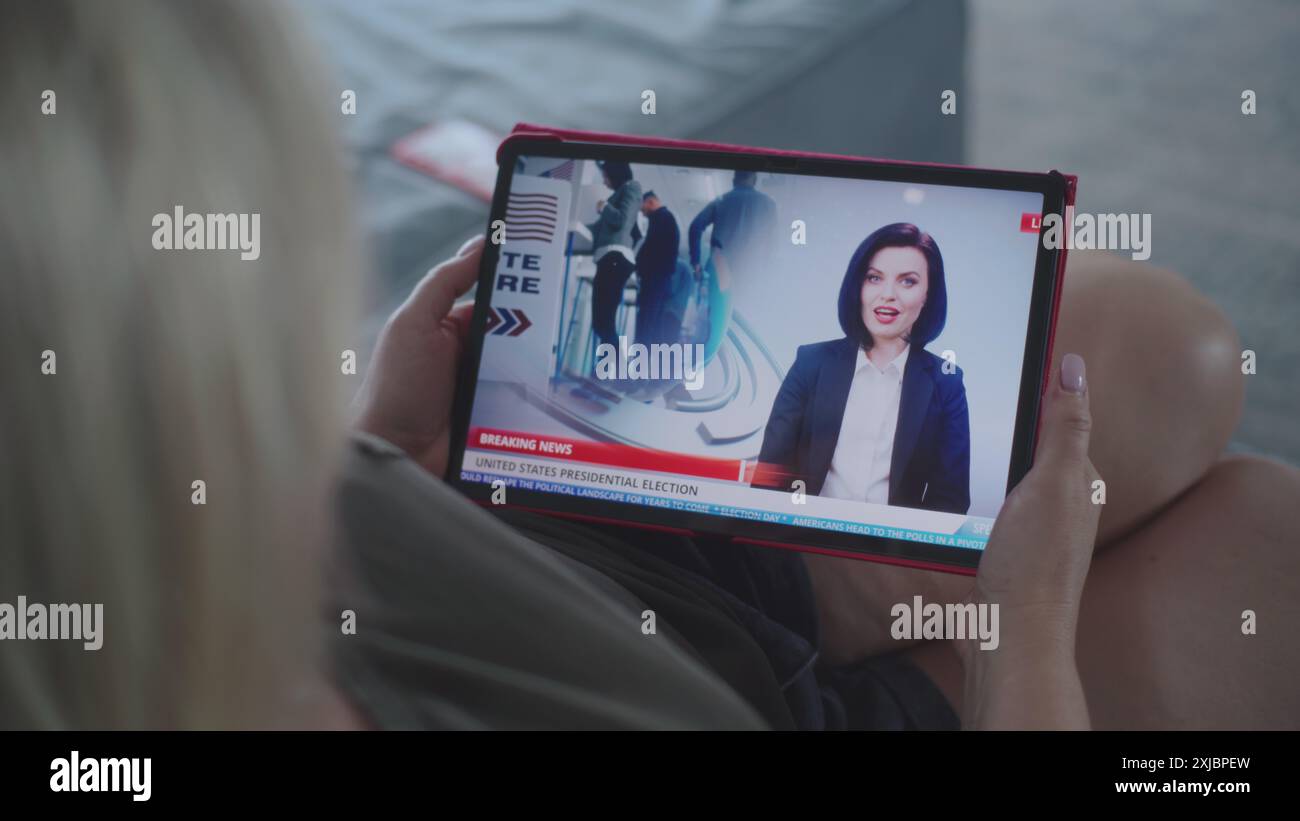 Tablet screen shows TV news broadcast with female newscaster. Caucasian ...