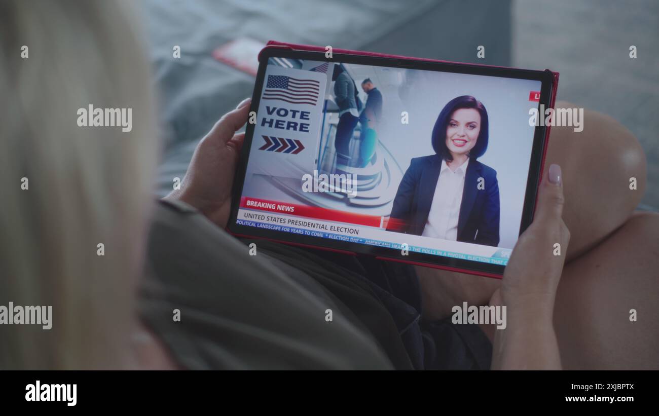 Tablet screen shows TV news broadcast with female newscaster. Caucasian ...