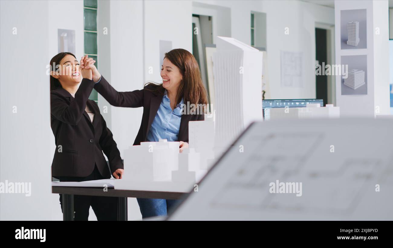 Architects doing high five gesture after finishing blueprints, feeling ...