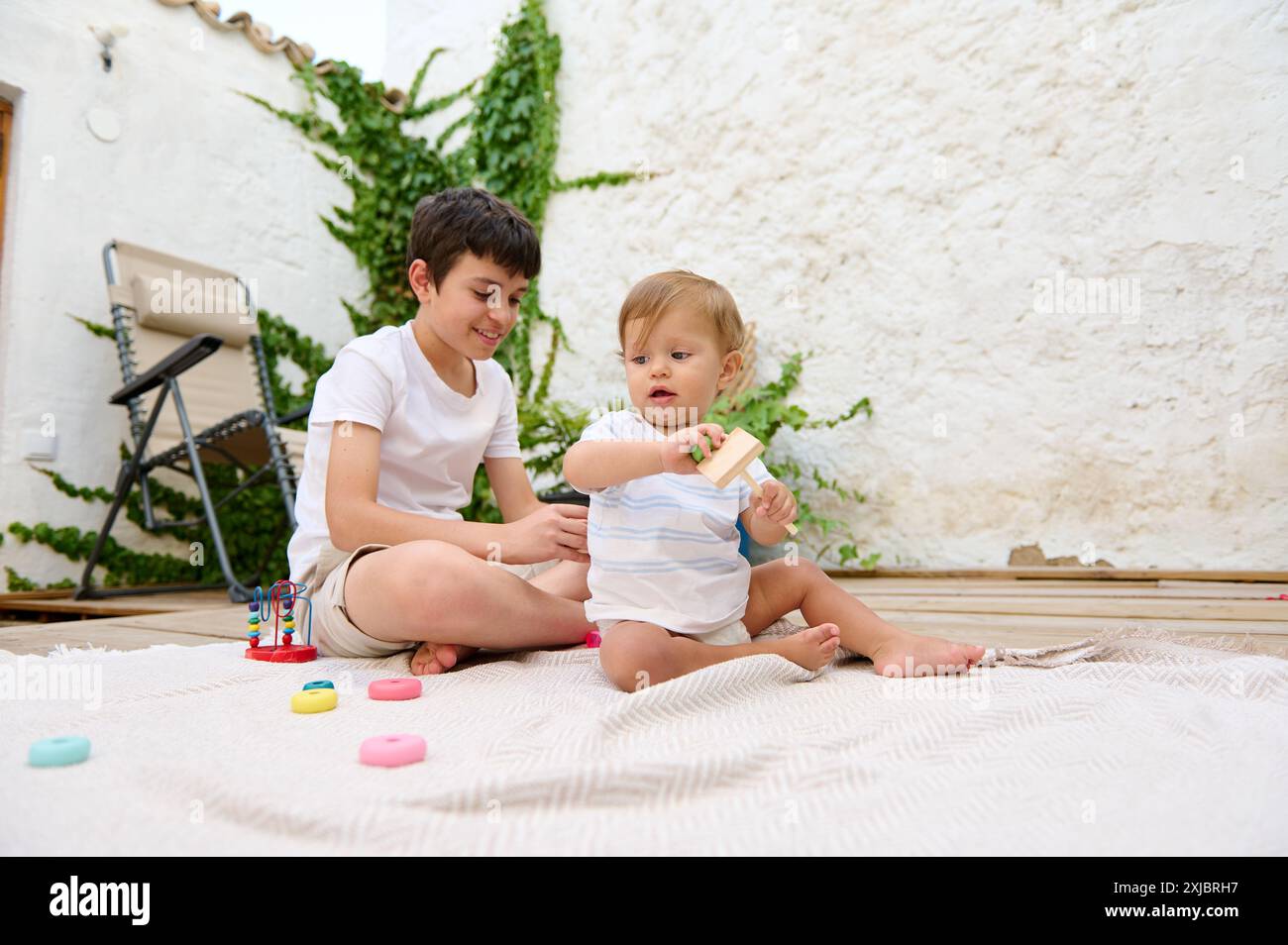 An older brother enjoys playing with his baby sibling in a summer ...