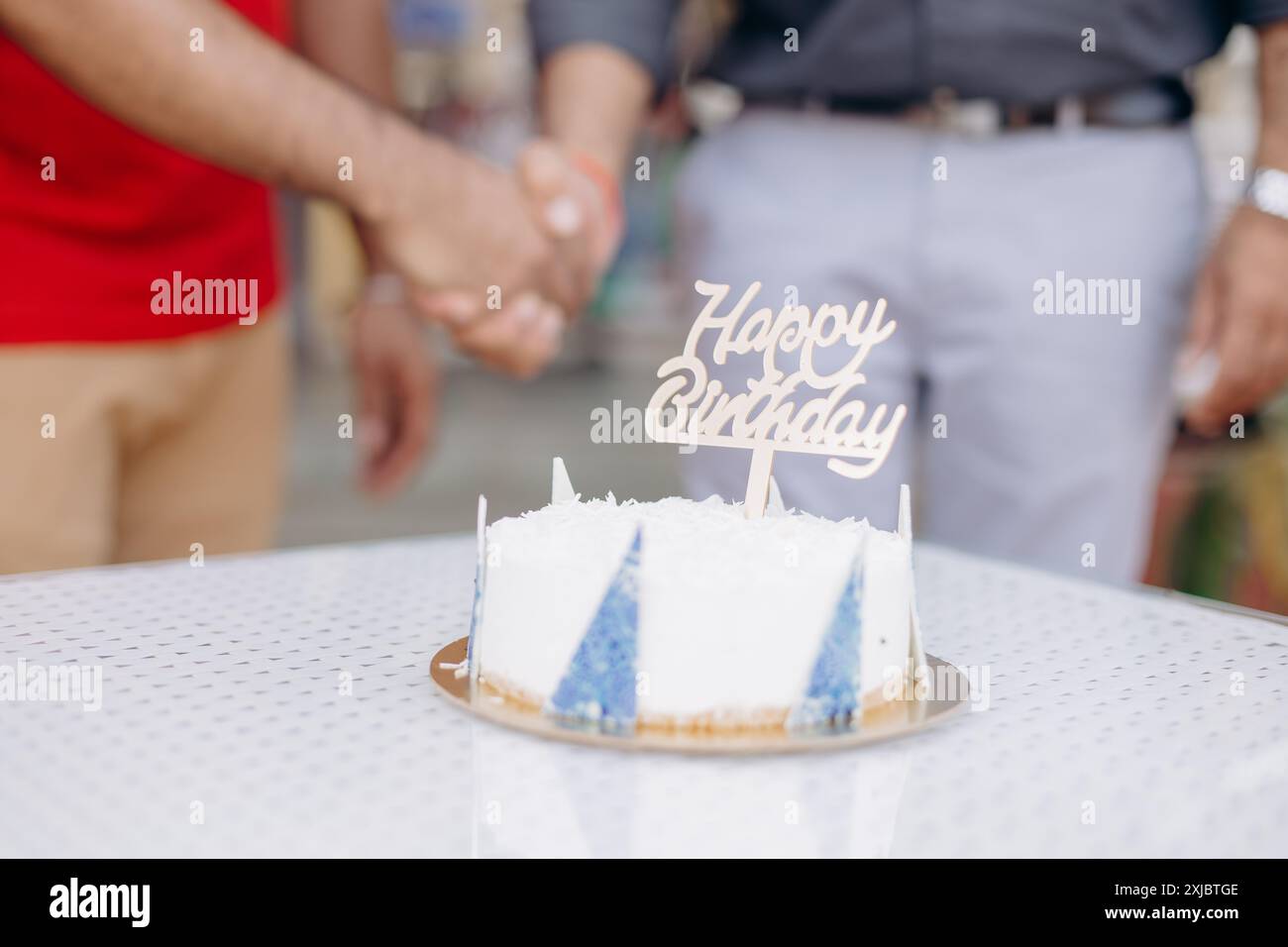 A photo of a birthday celebration with a handshake, focusing on the ...