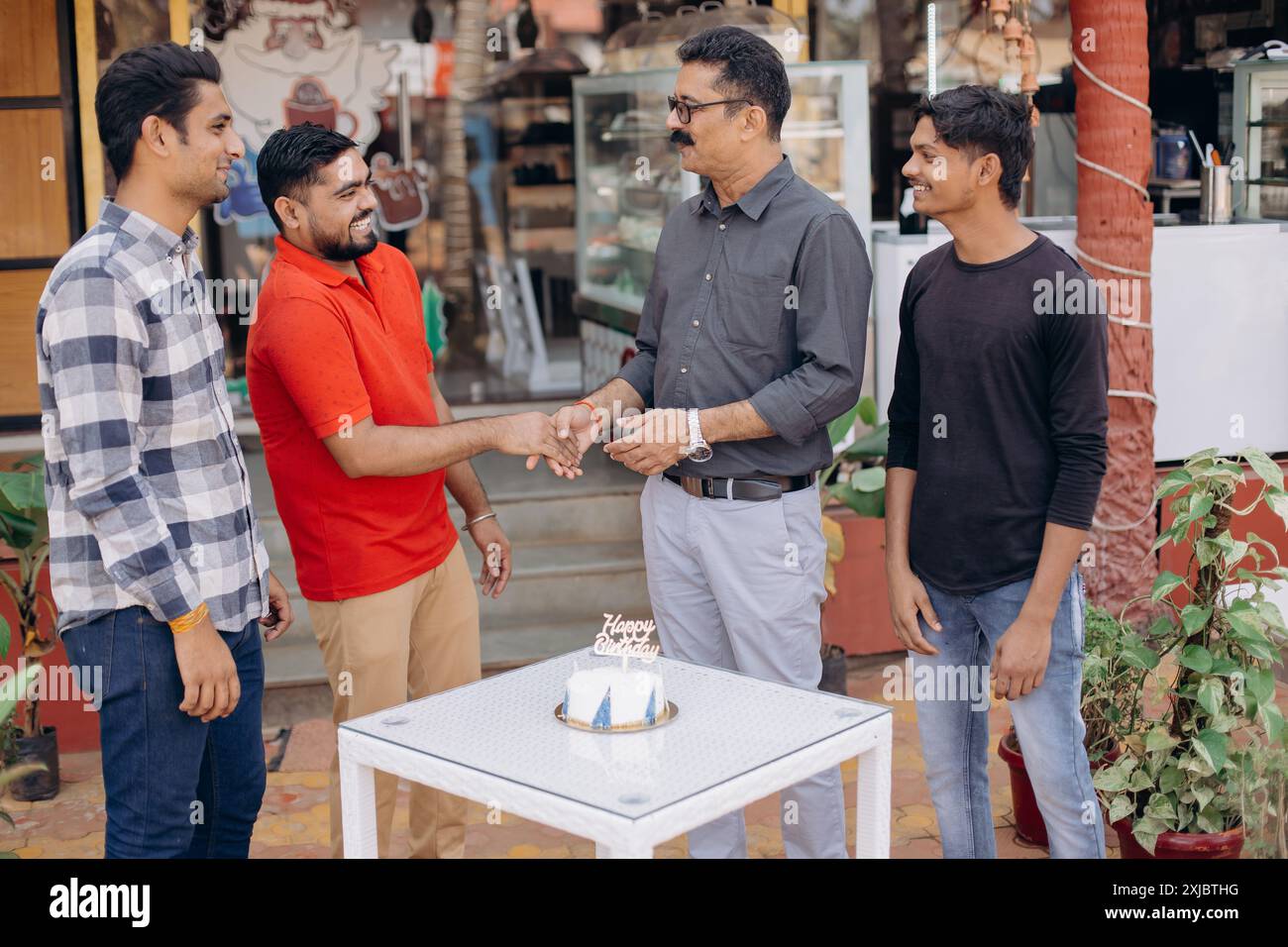 Friends celebrating a birthday outside, sharing a cake, exchanging ...