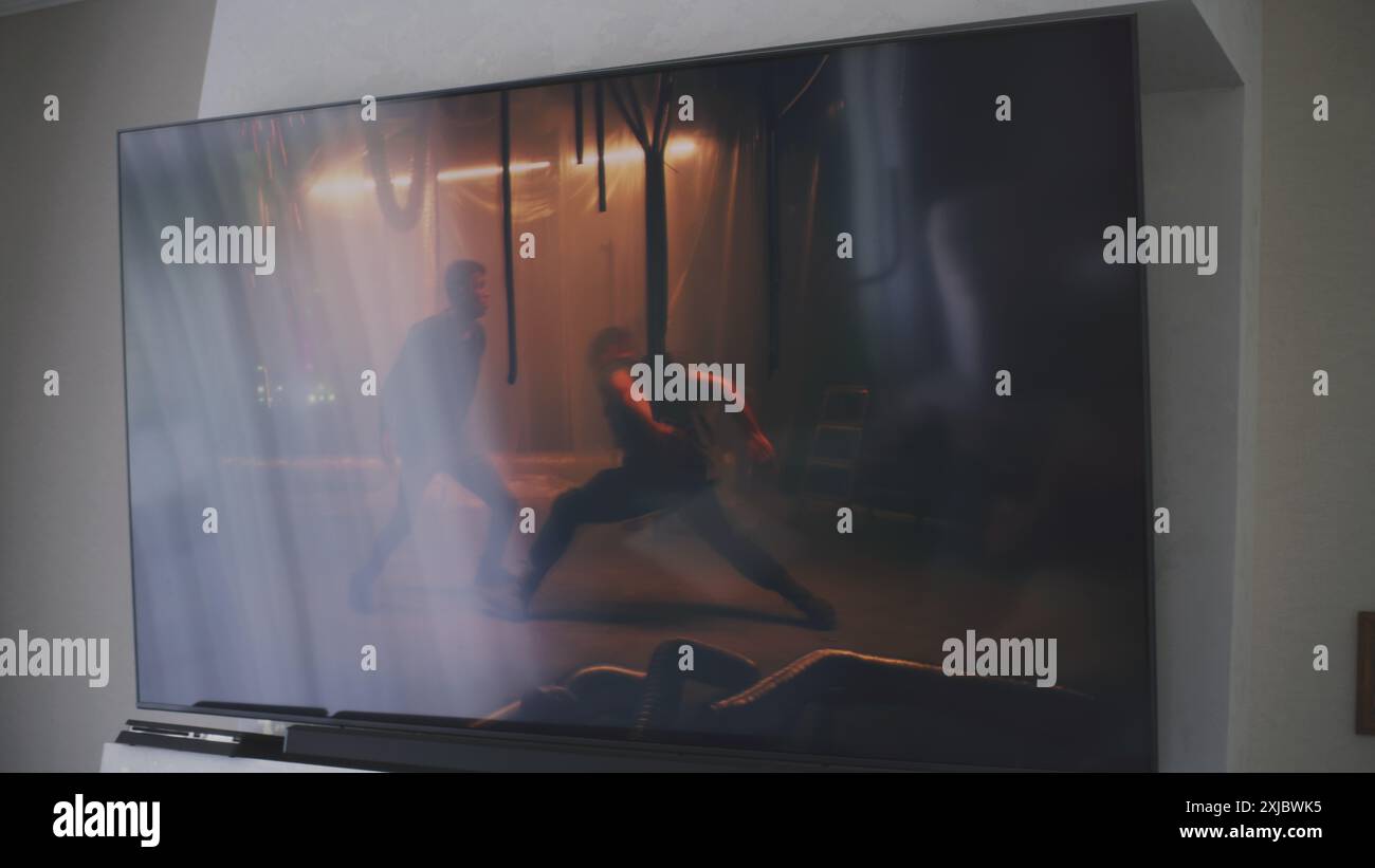 Big TV screen with displayed action movie hanging on wall in cozy ...