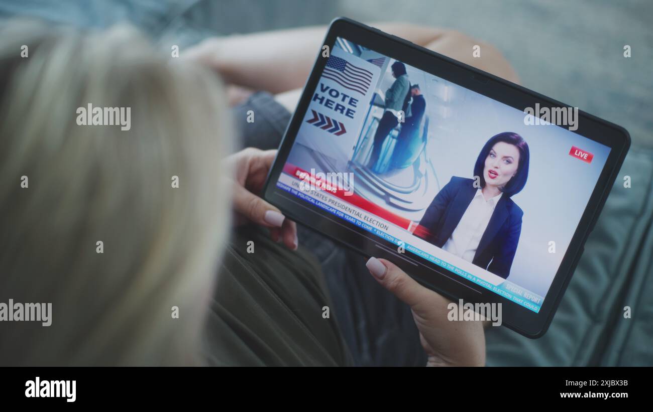 Tablet screen shows TV news broadcast with female newscaster. Caucasian ...