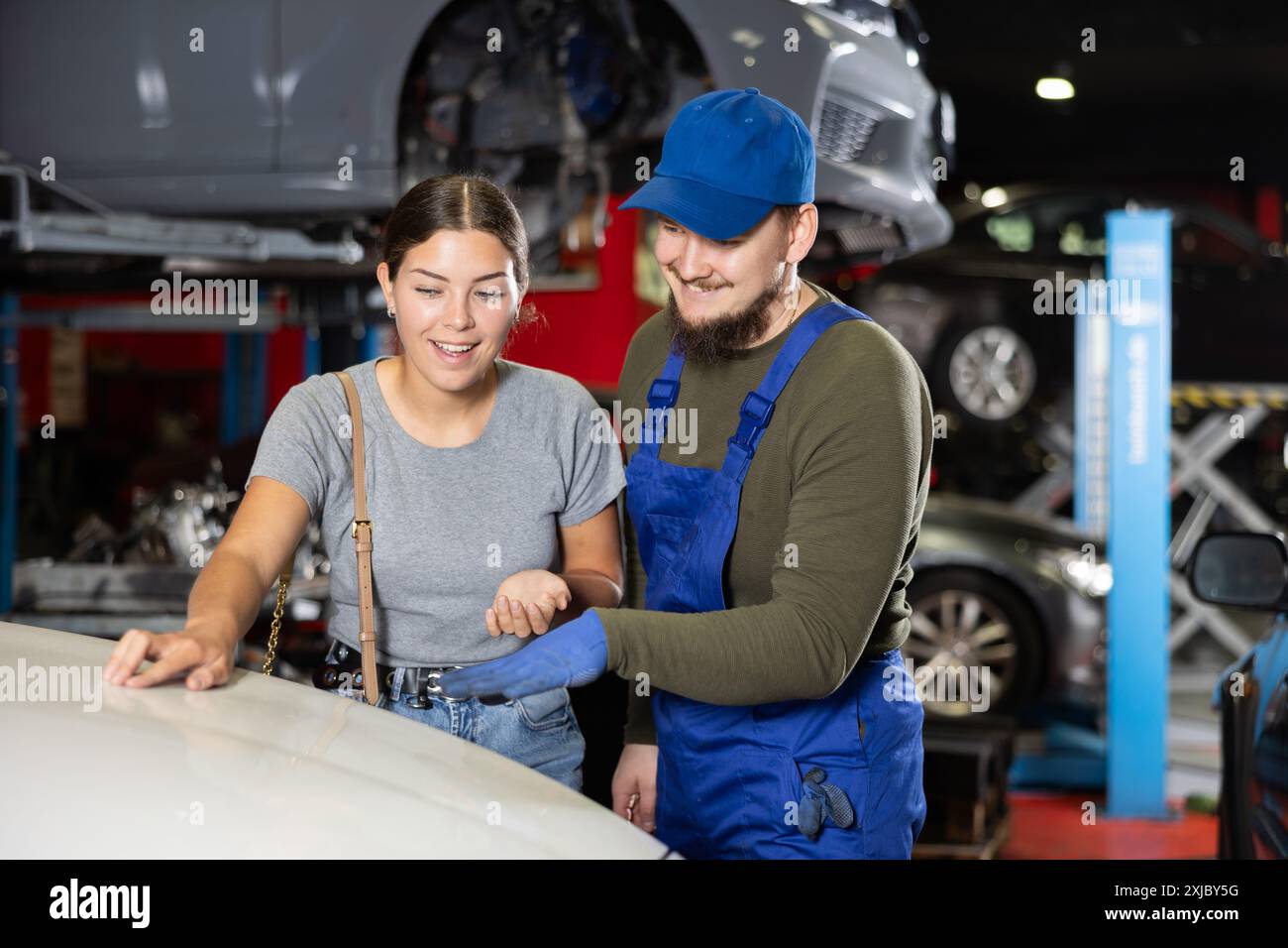 Mechanic guy consulting woman client on auto repair Stock Photo - Alamy