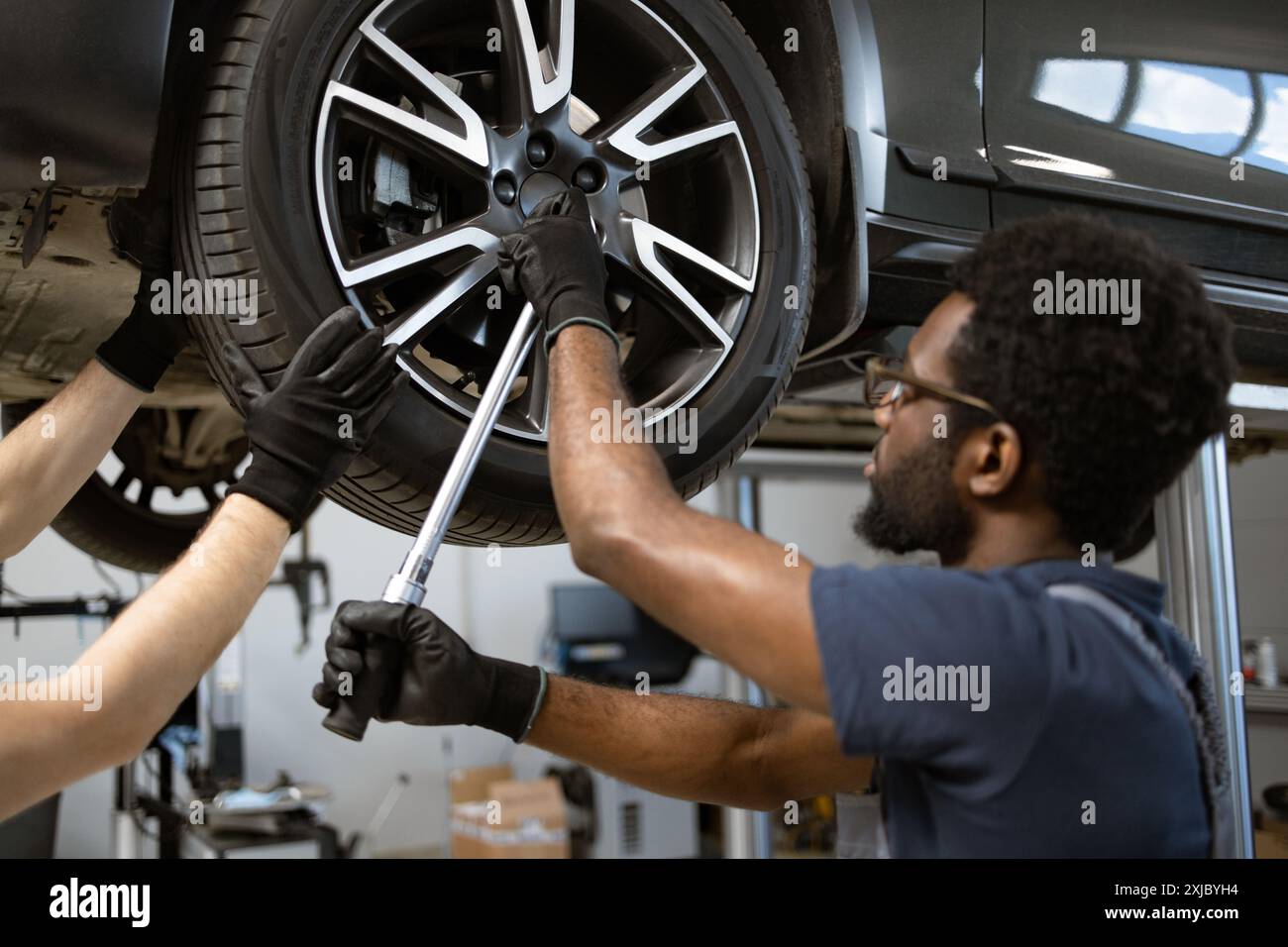 Mechanics working on car wheel in auto repair shop Stock Photo - Alamy