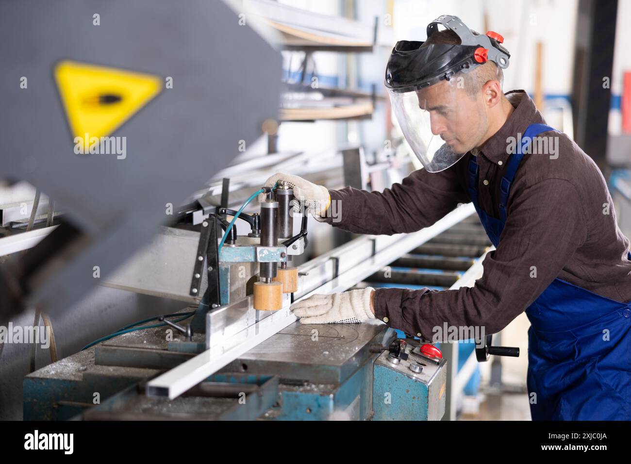 Workman cutting PVC profile on industrial machine in production ...