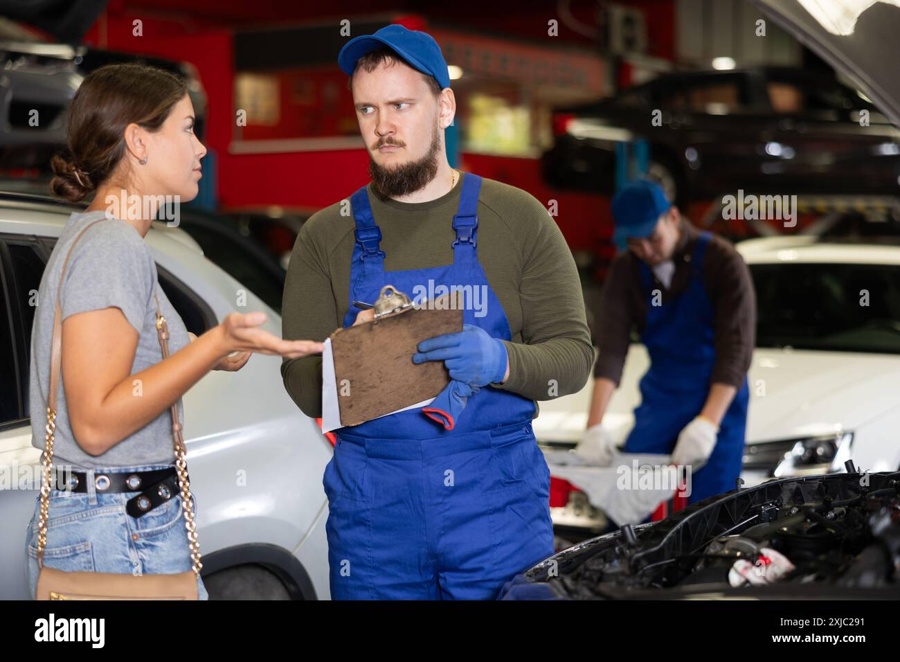 Mechanic guy signs agreement with young woman client Stock Photo - Alamy