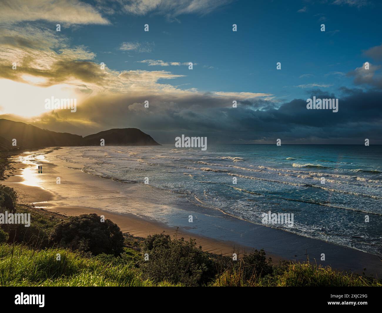Couple walking together dramatic beach scene, East Coast,North Island ...