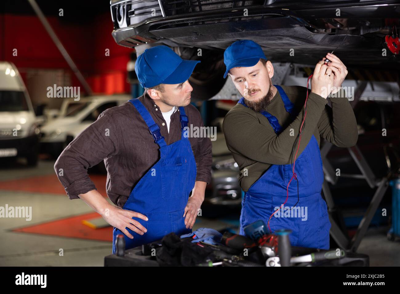 Two auto mechanics work together to diagnose an engine using a ...