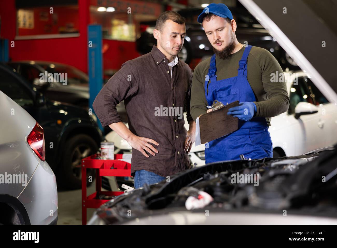 Owner of car explains to mechanic what needs to be repaired. Auto ...