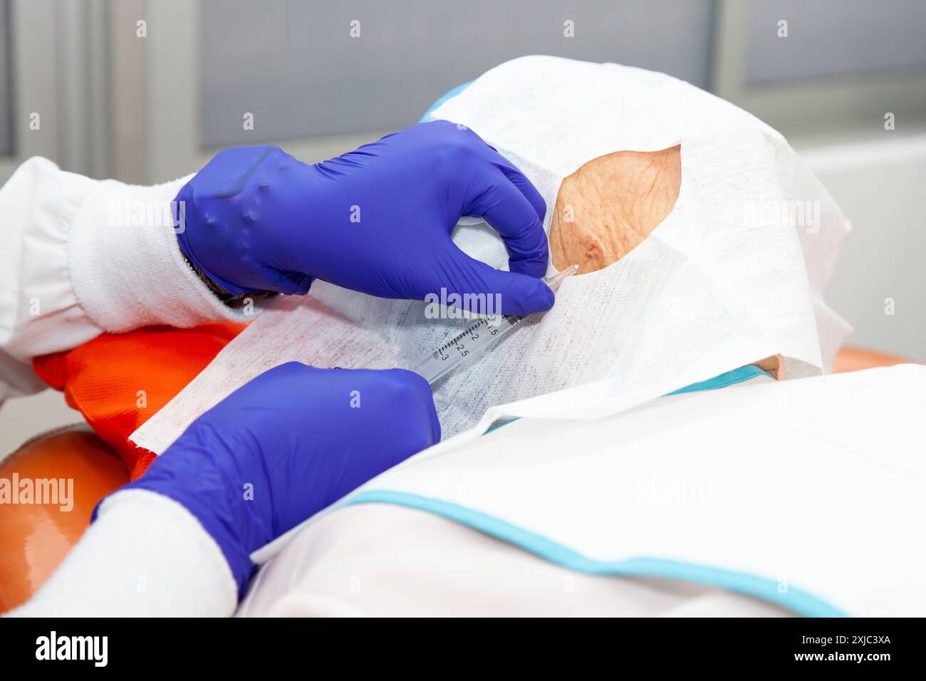 Dermatologist carrying out a skin biopsy on the face of a senior adult ...