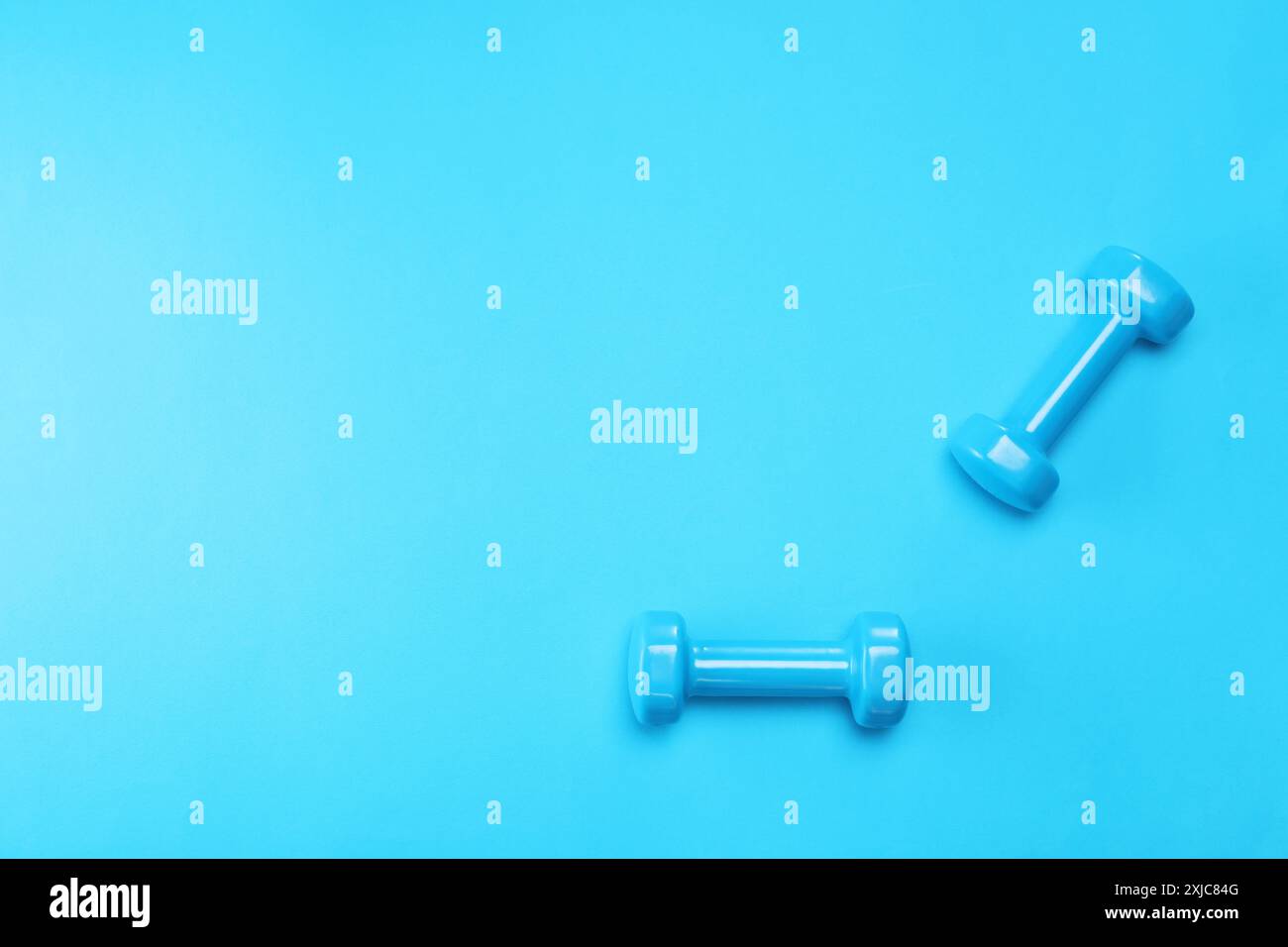Two dumbbells on light blue background, top view. Space for text Stock ...