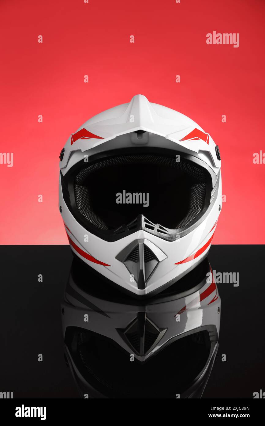 Modern motorcycle helmet with visor on mirror surface against red ...
