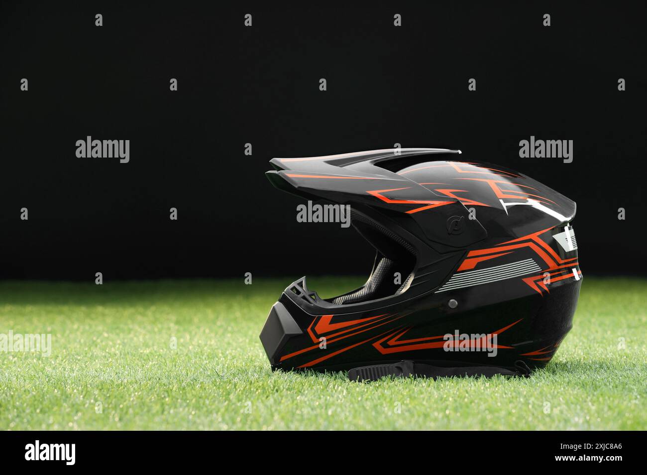 Modern motorcycle helmet with visor on green grass against black ...