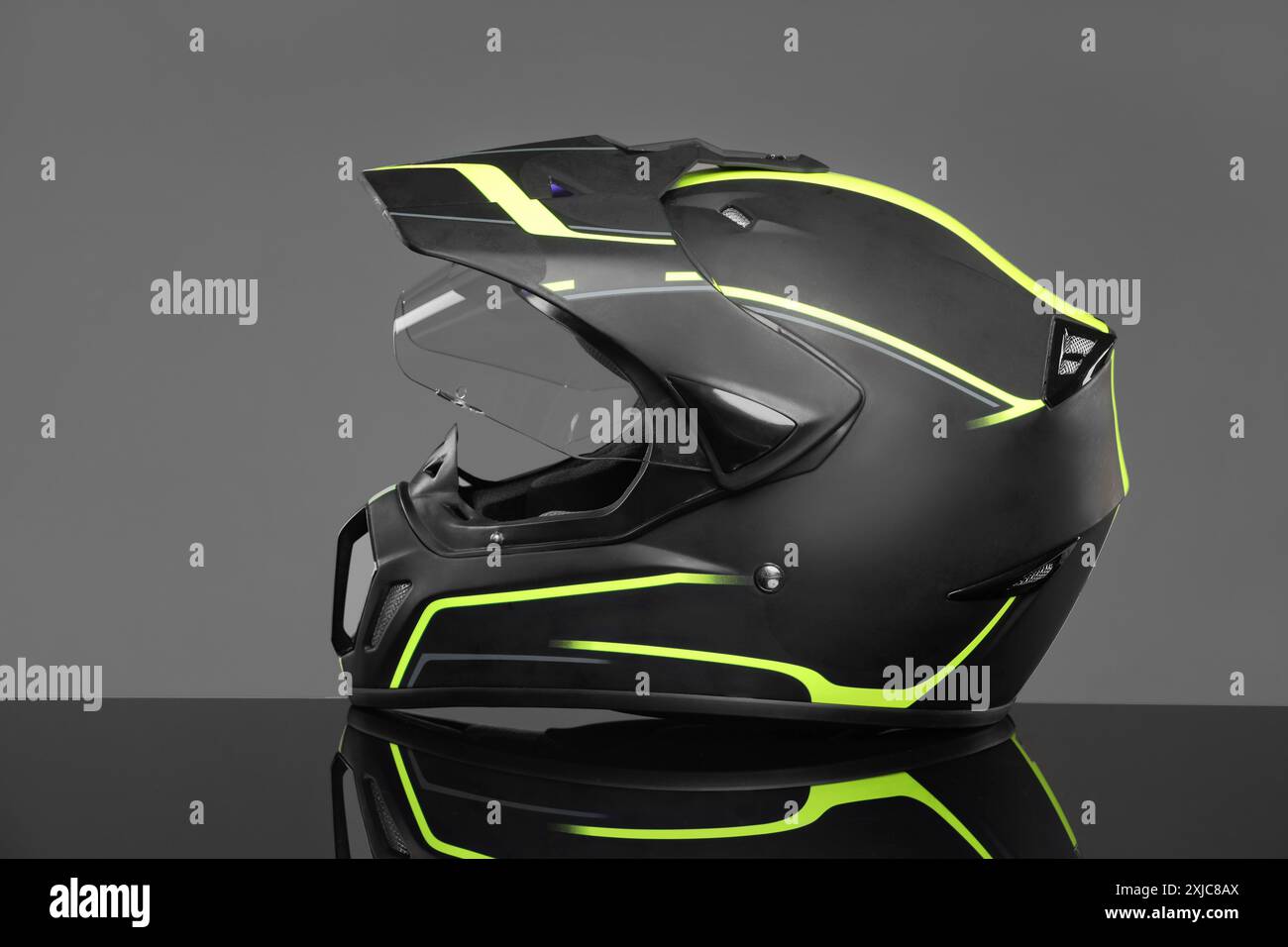 Modern motorcycle helmet with visor on mirror surface against light ...