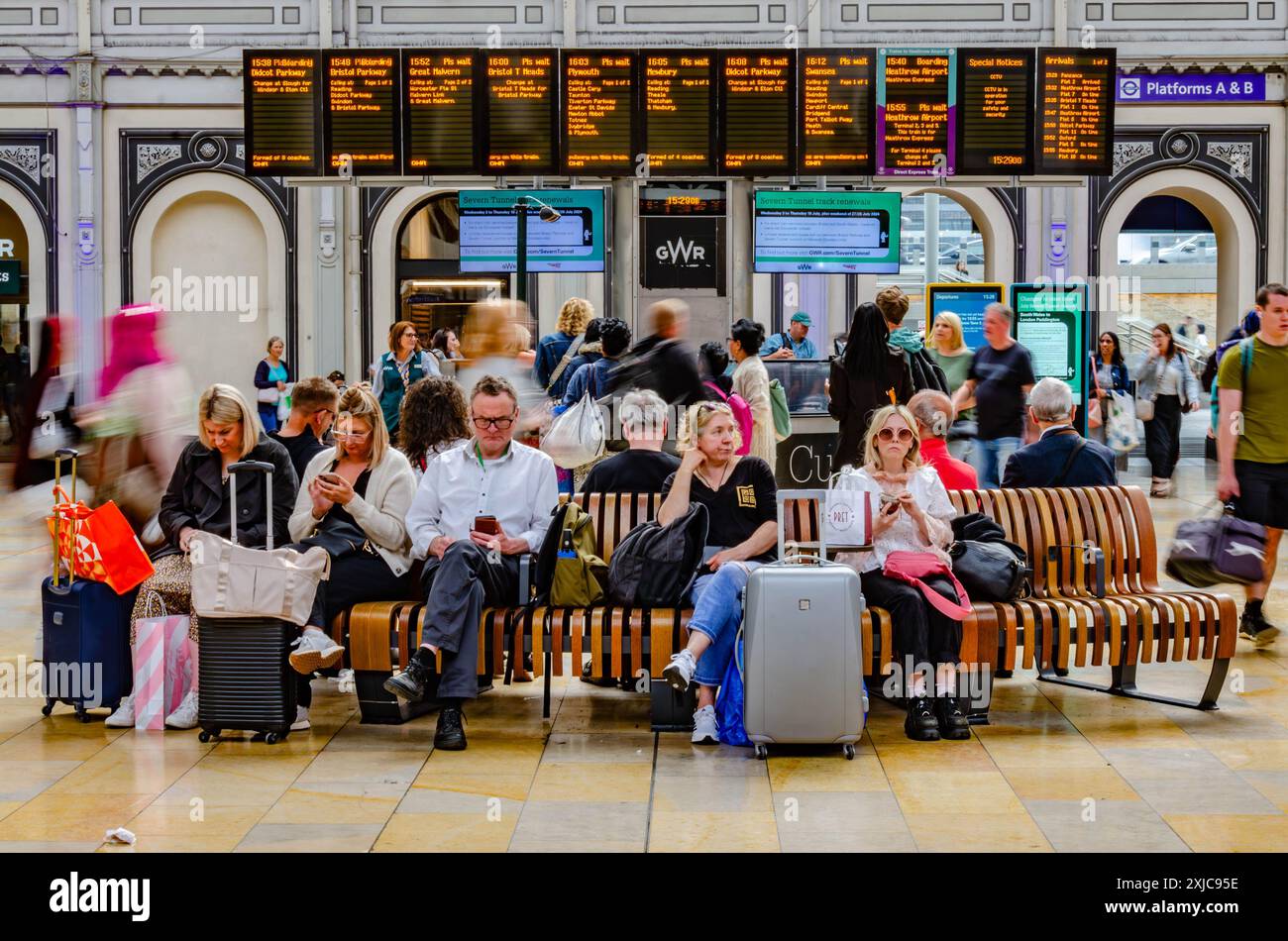 Passengers sit and wait for their trains at Paddington Railway Station. Electronic departure ...