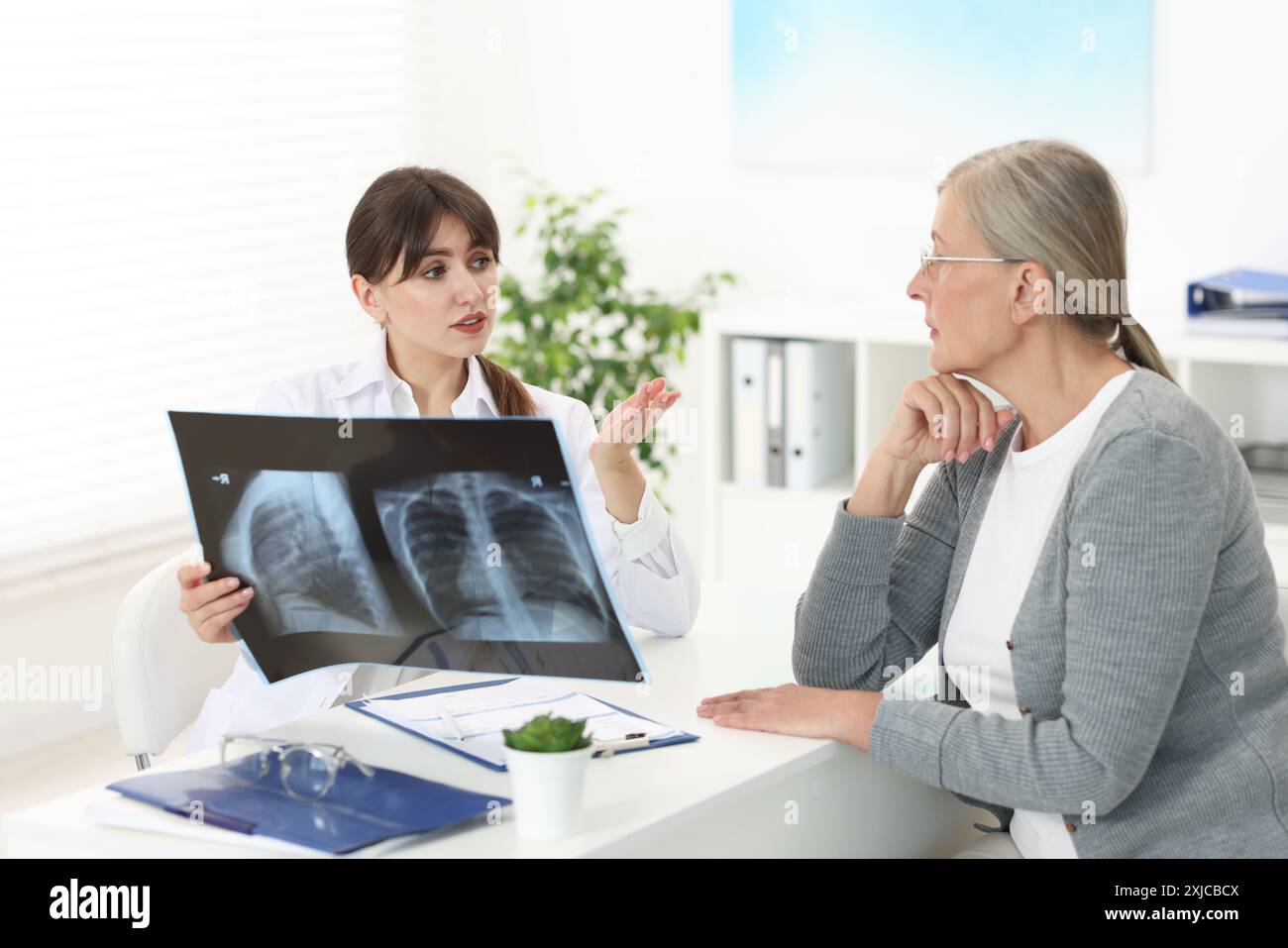 Lung disease. Doctor with chest x-ray consulting patient in clinic ...
